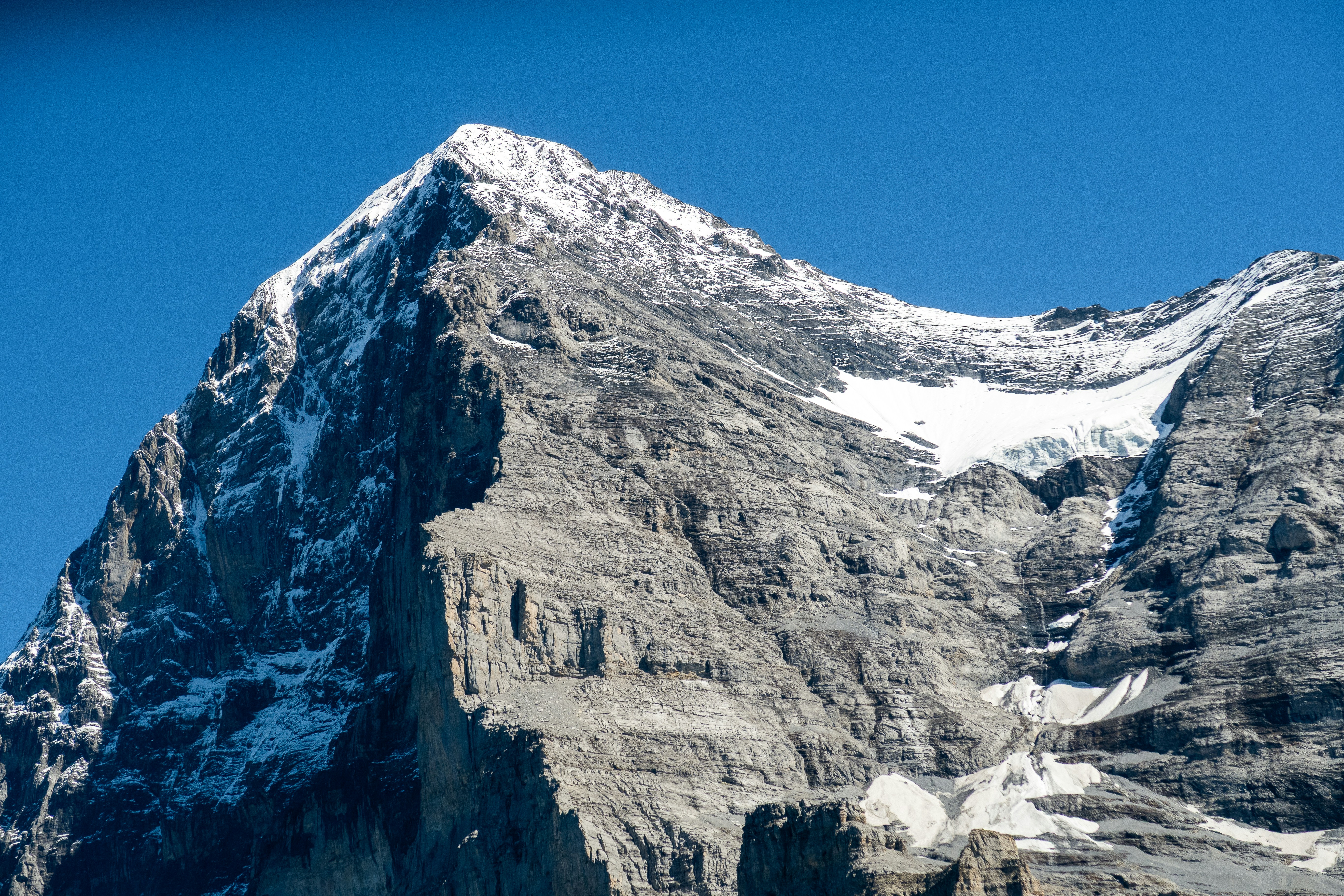 Viewing a mountain top. | Snow-capped mountain peak against a clear blue sky