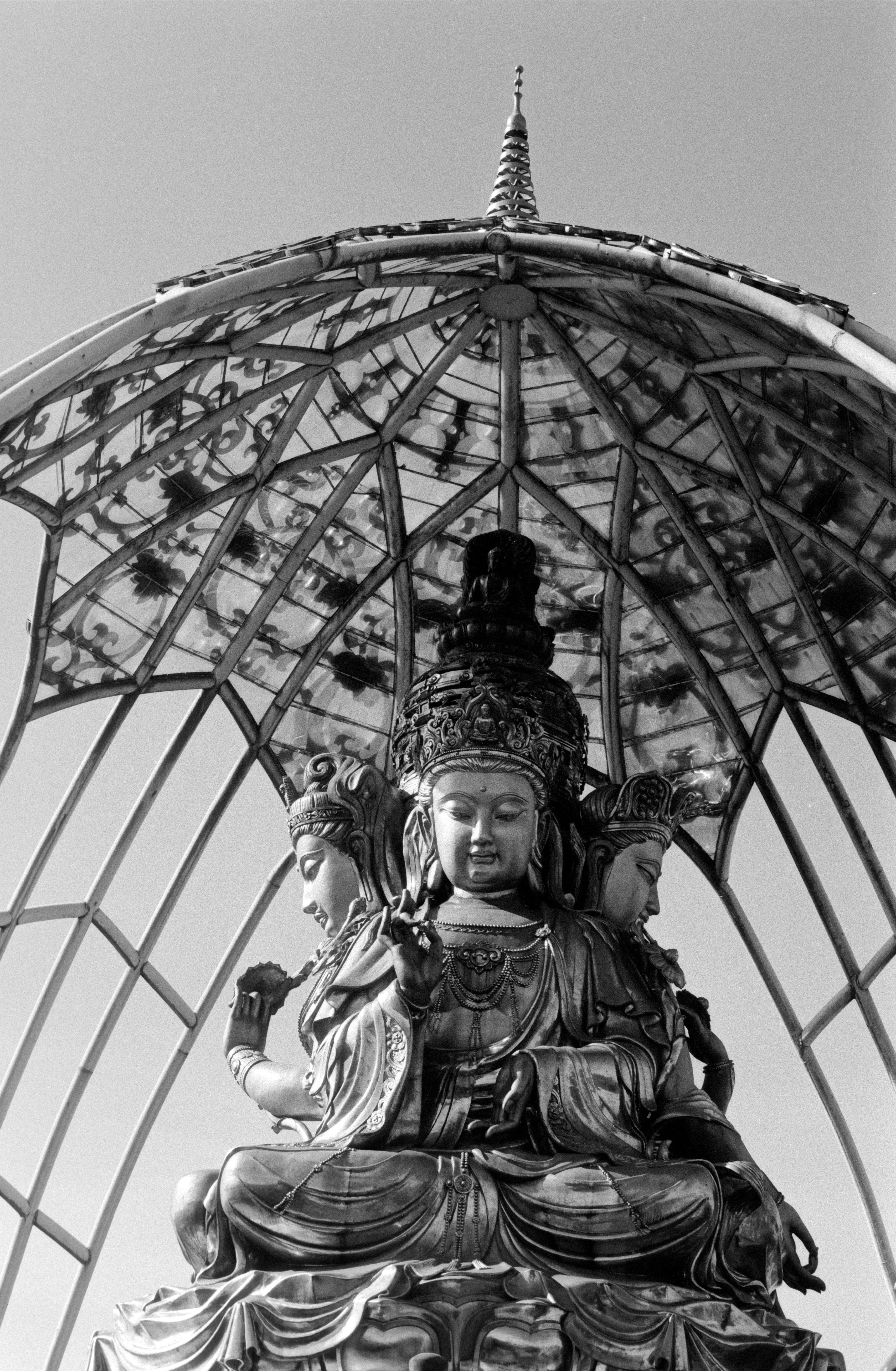Three-Faced Buddha Beneath an Intricate Glass Dome