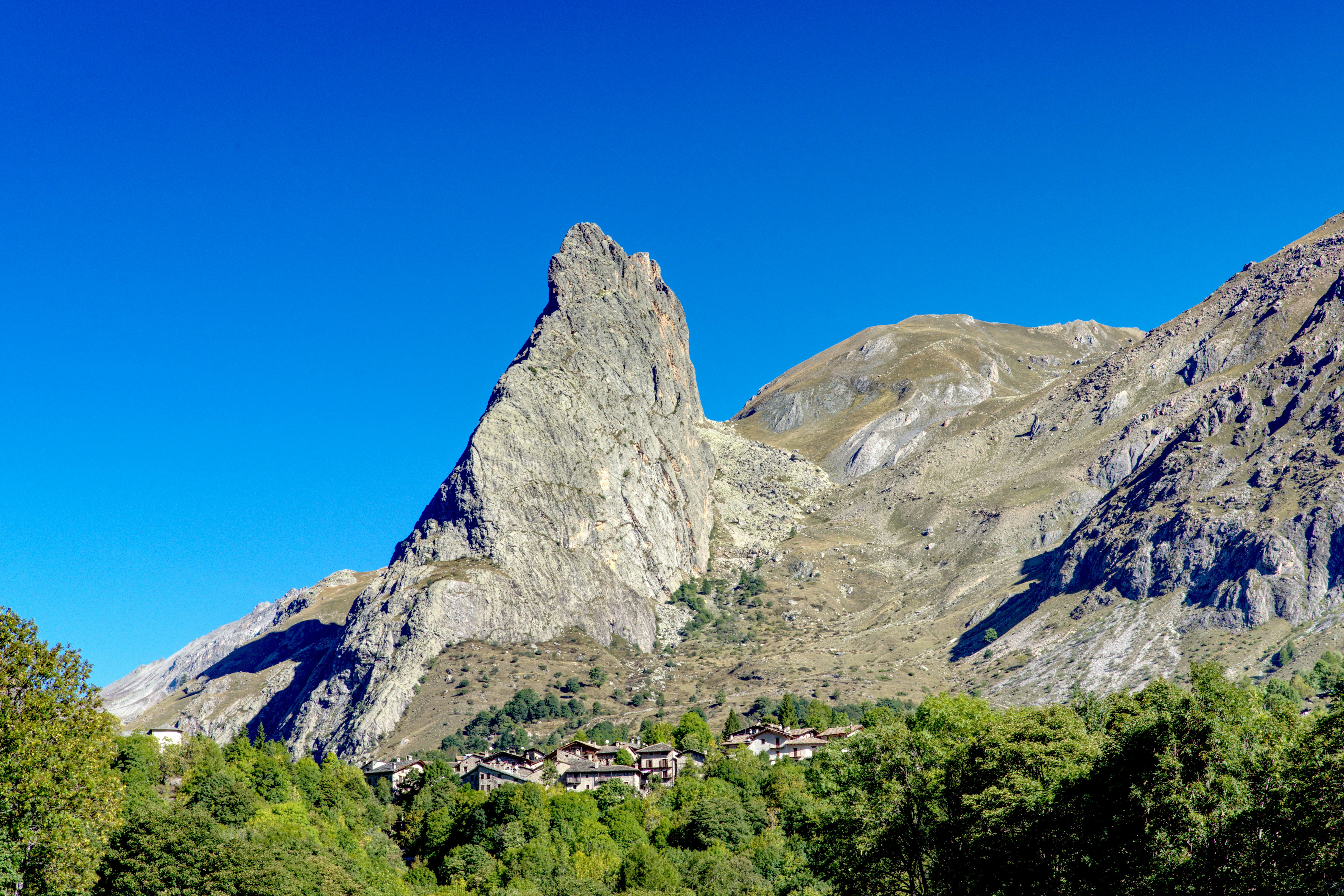 Chiappera e Rocca Provenzale | Jagged mountain peak above a village and forest