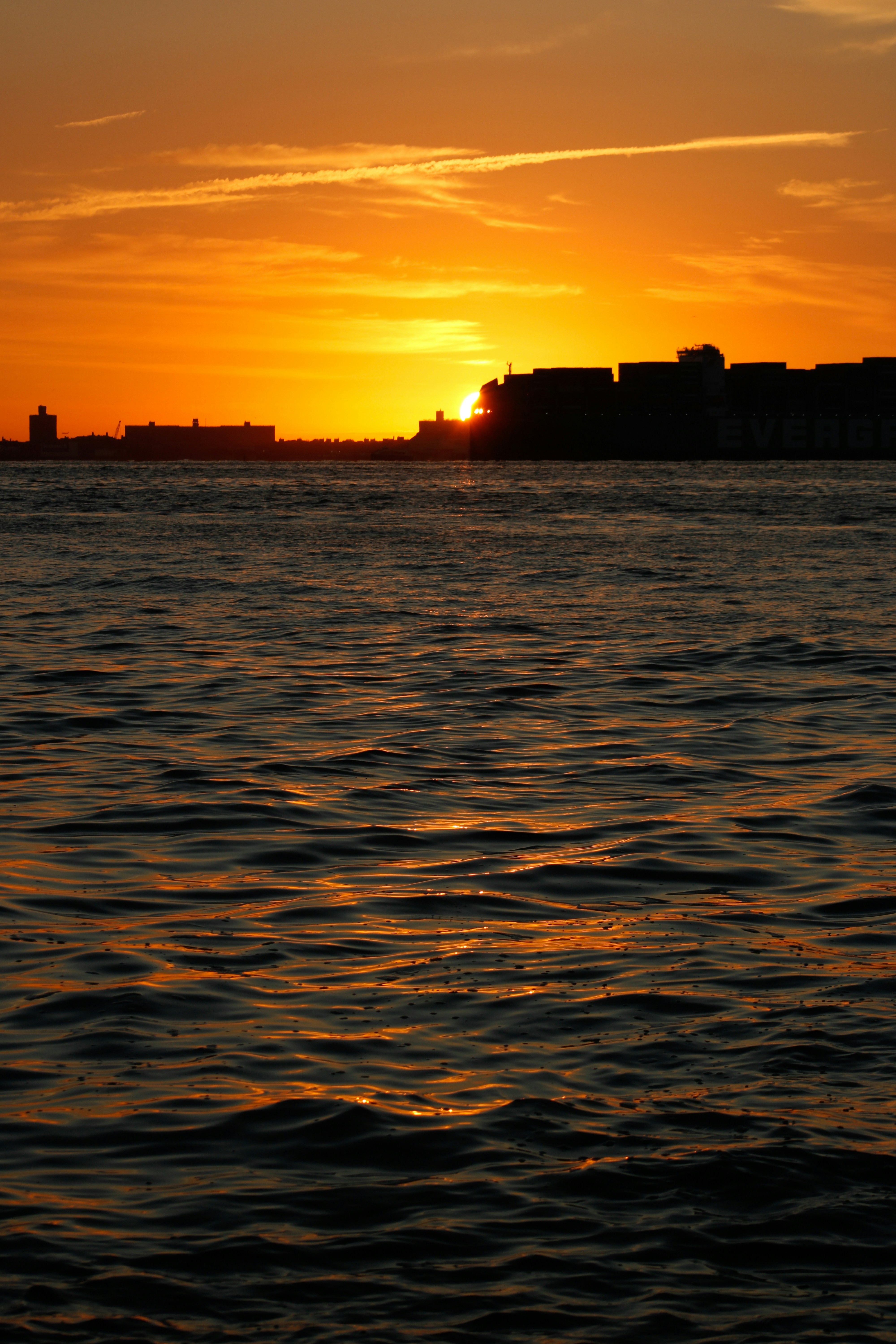 Sunset over the water with city skyline silhouette