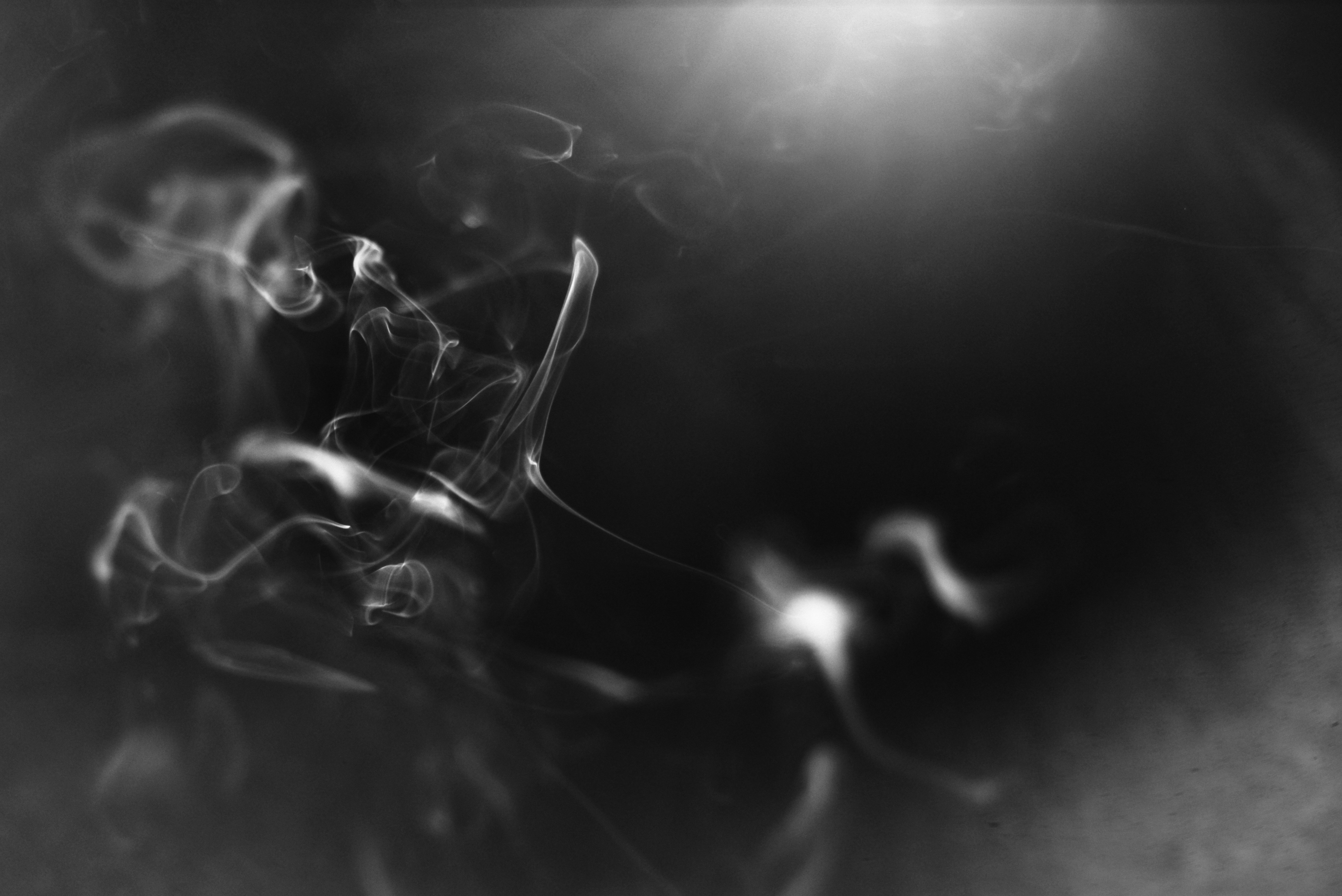 Wisps of smoke swirl in dark, moody lighting.
