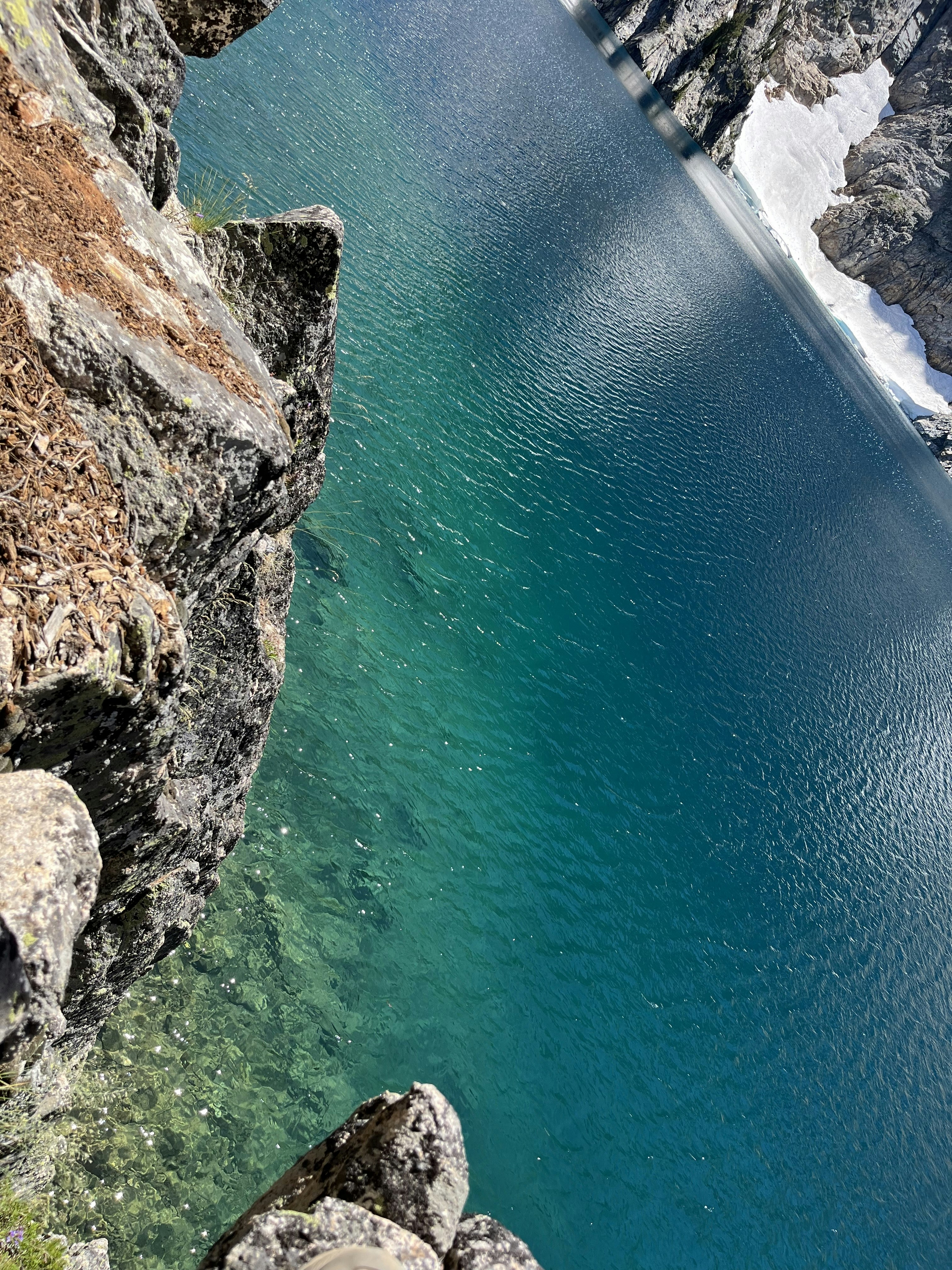 Turquoise alpine lake surrounded by rocky cliffs and snow