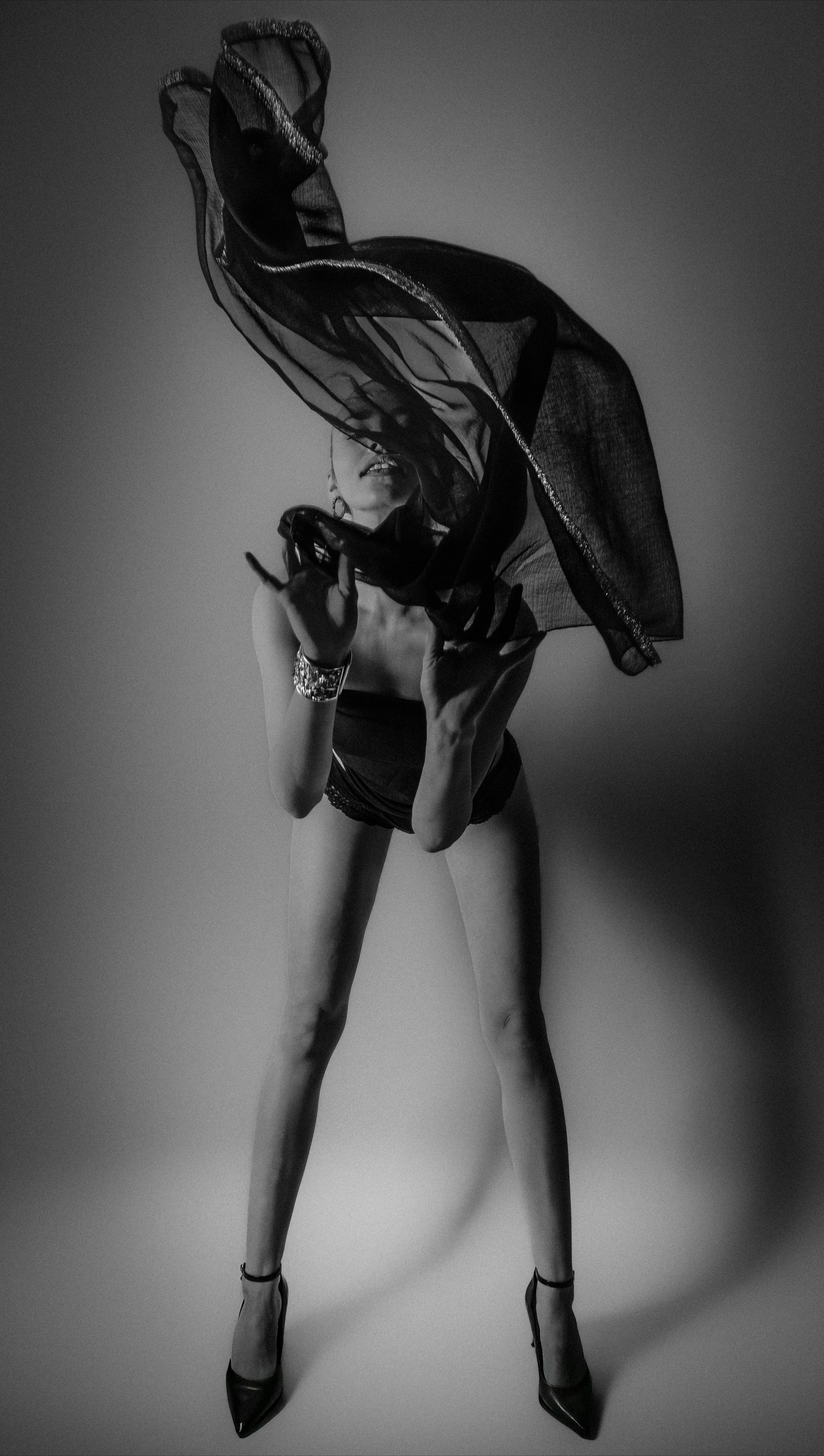 Woman in black bodysuit with flowing sheer fabric