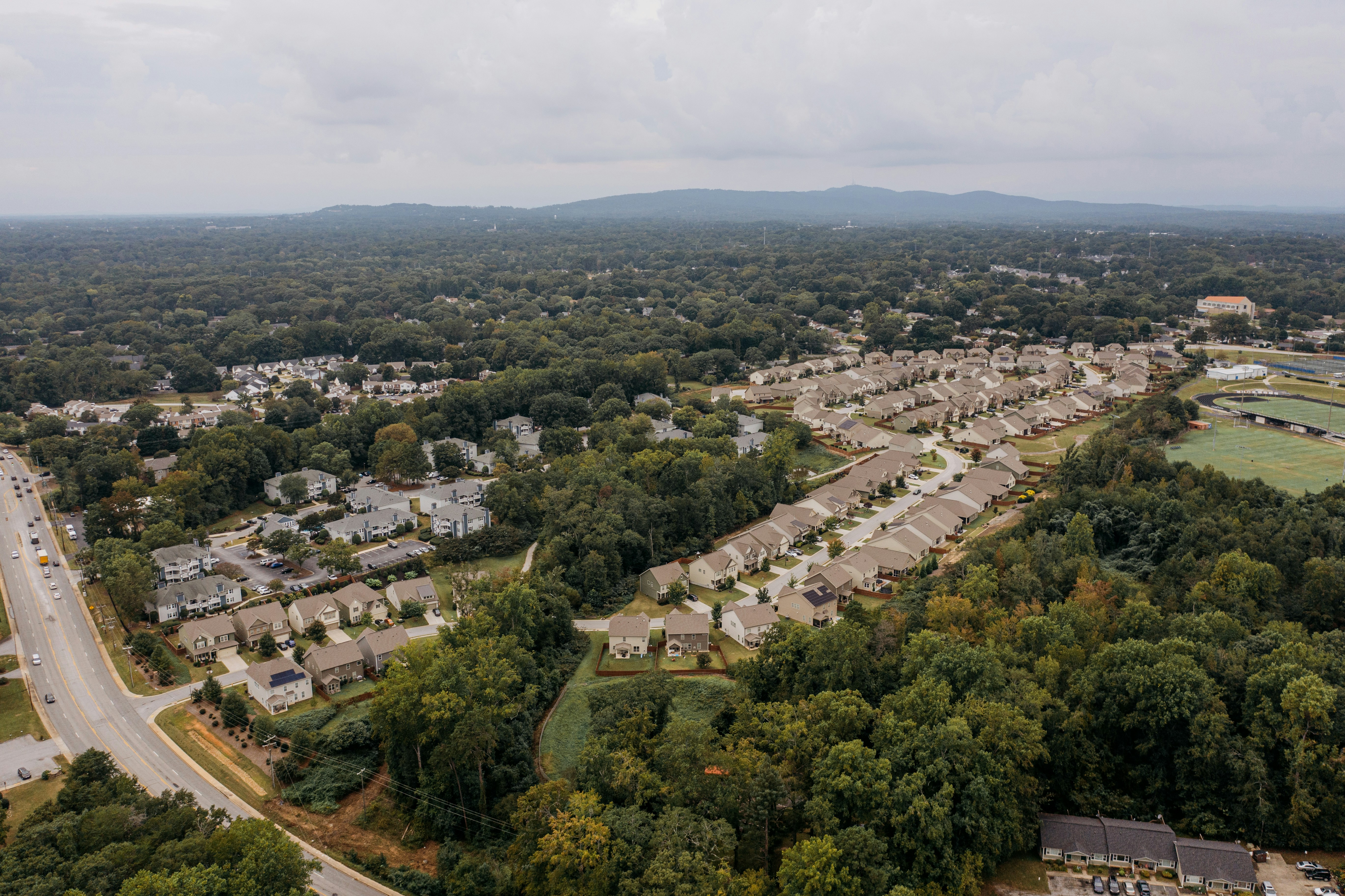 Aerial view of a suburban neighborhood with dense trees.
