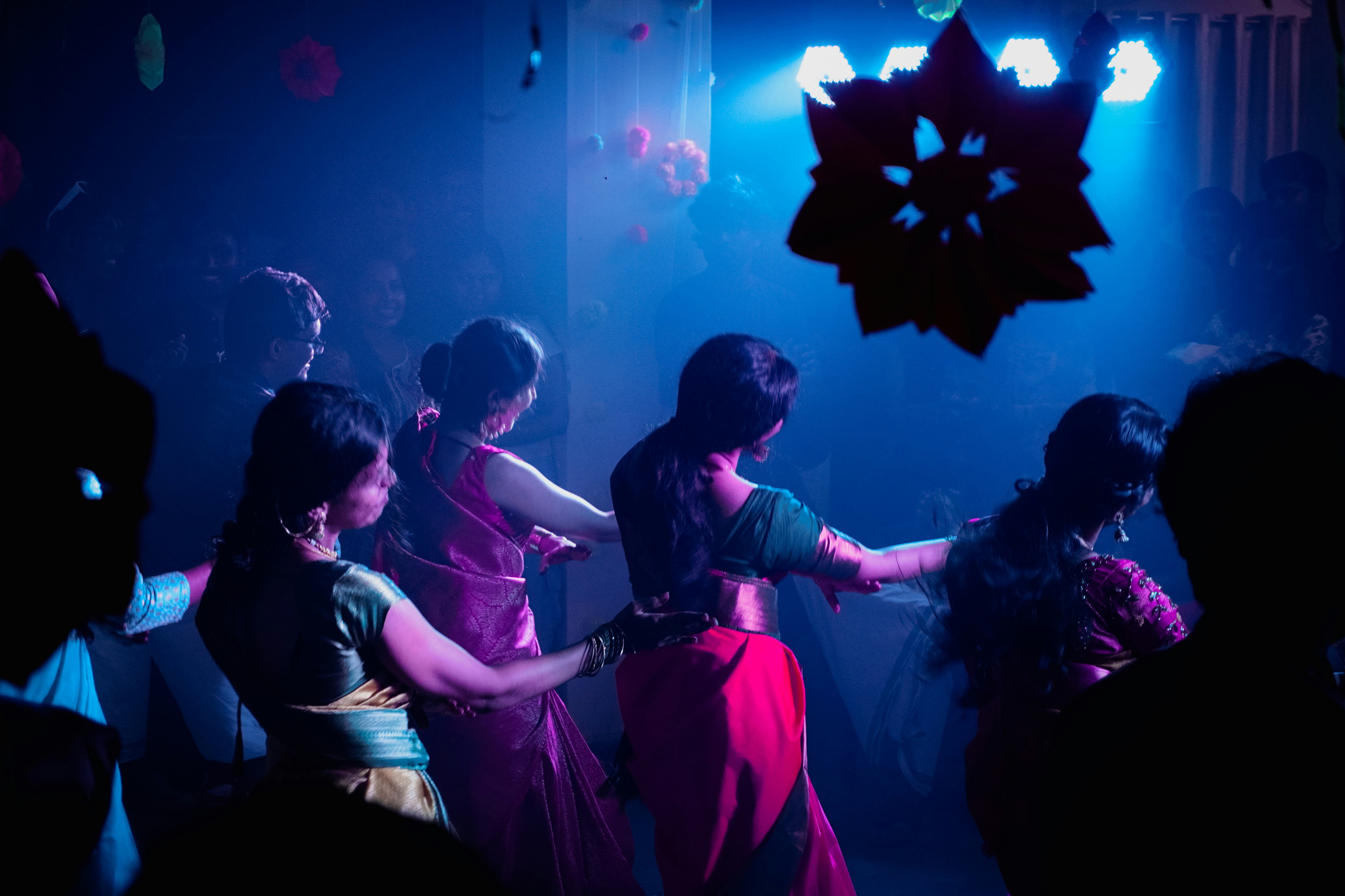 Line of dancers under blue haze as a star-shaped lantern hovers above