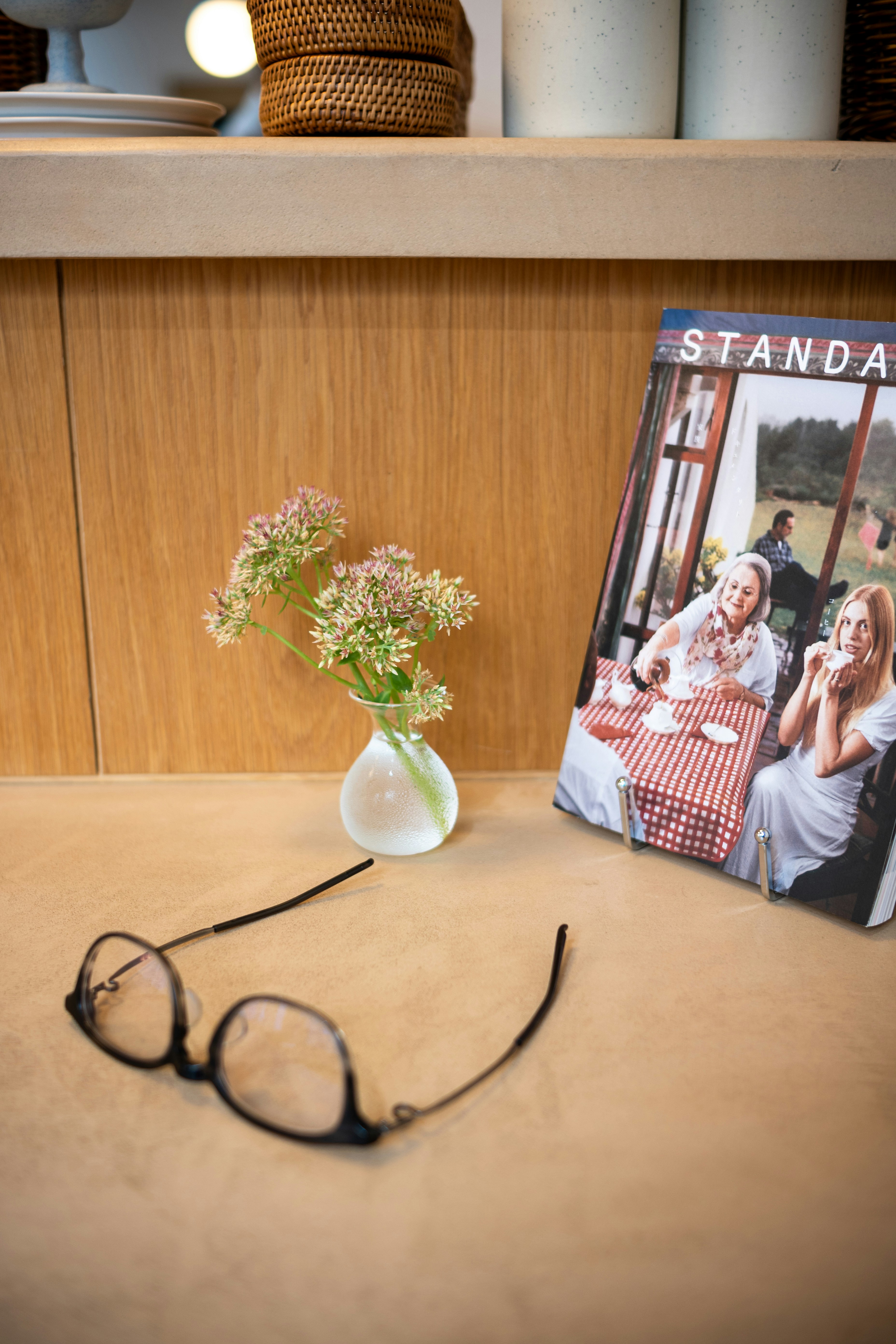 Glasses and flowers on a wooden surface with magazine.