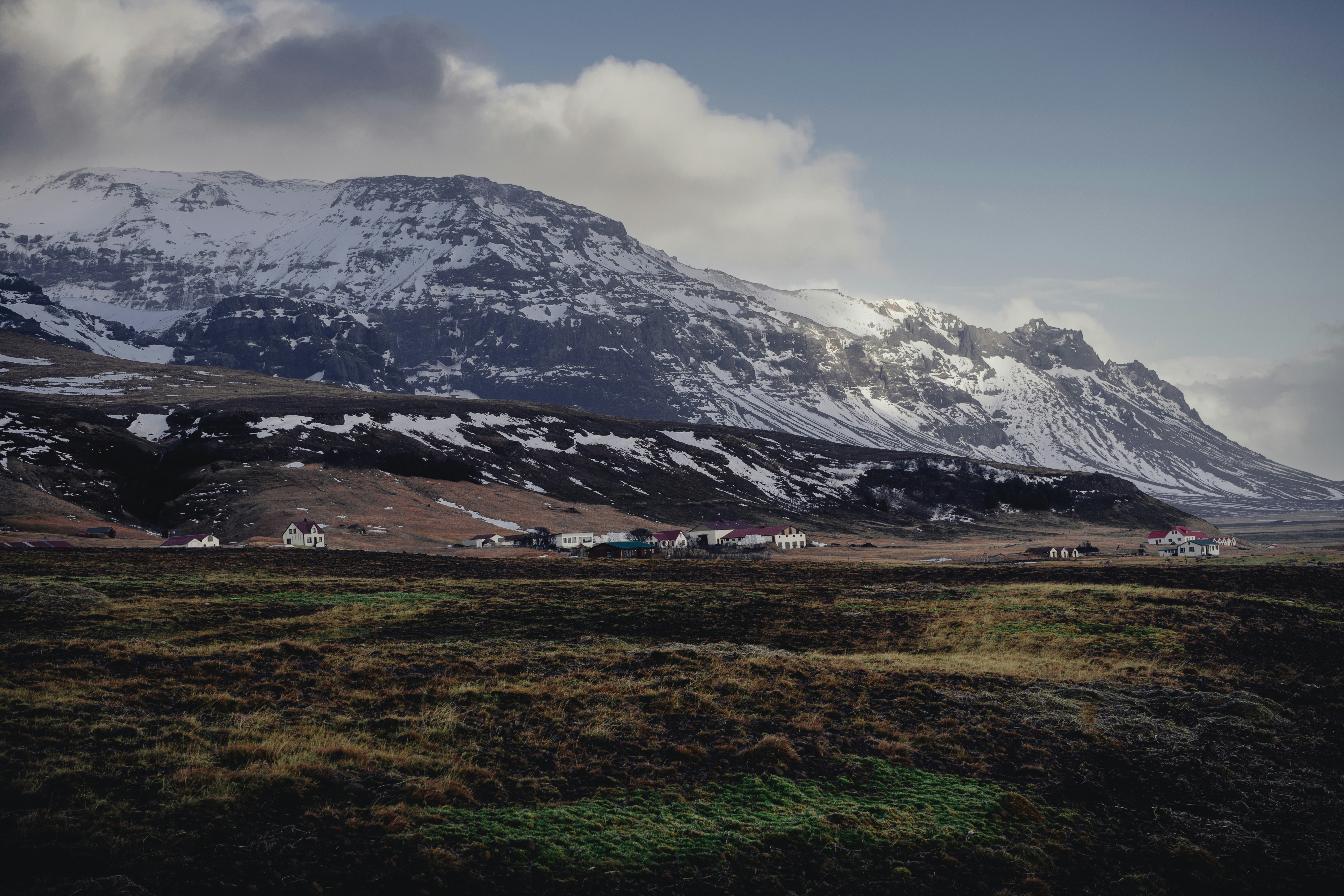 Iceland | Snow-capped mountains overlook a rural village landscape.