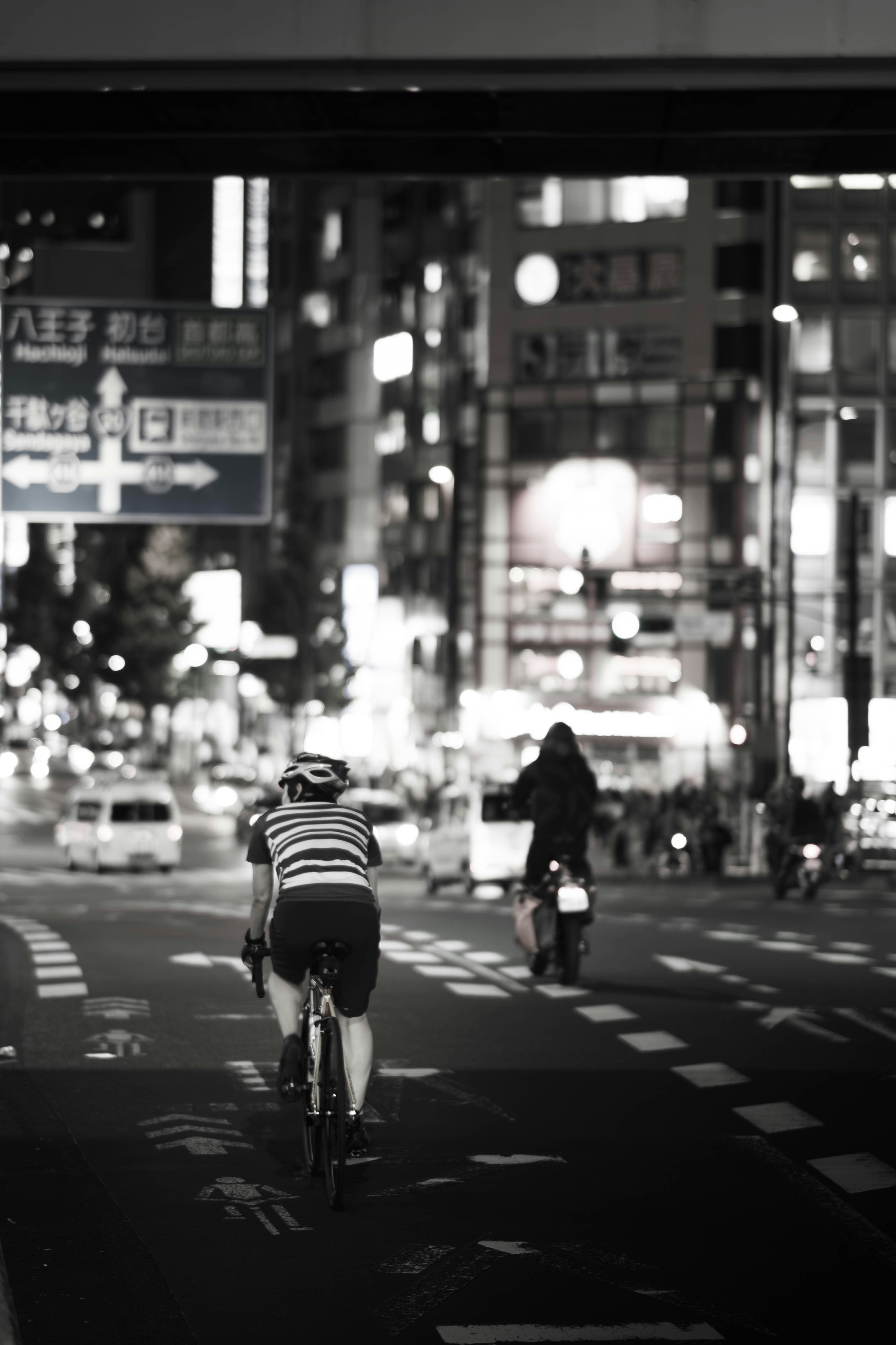 Bike on main road | Cyclist rides through a busy city street at night.