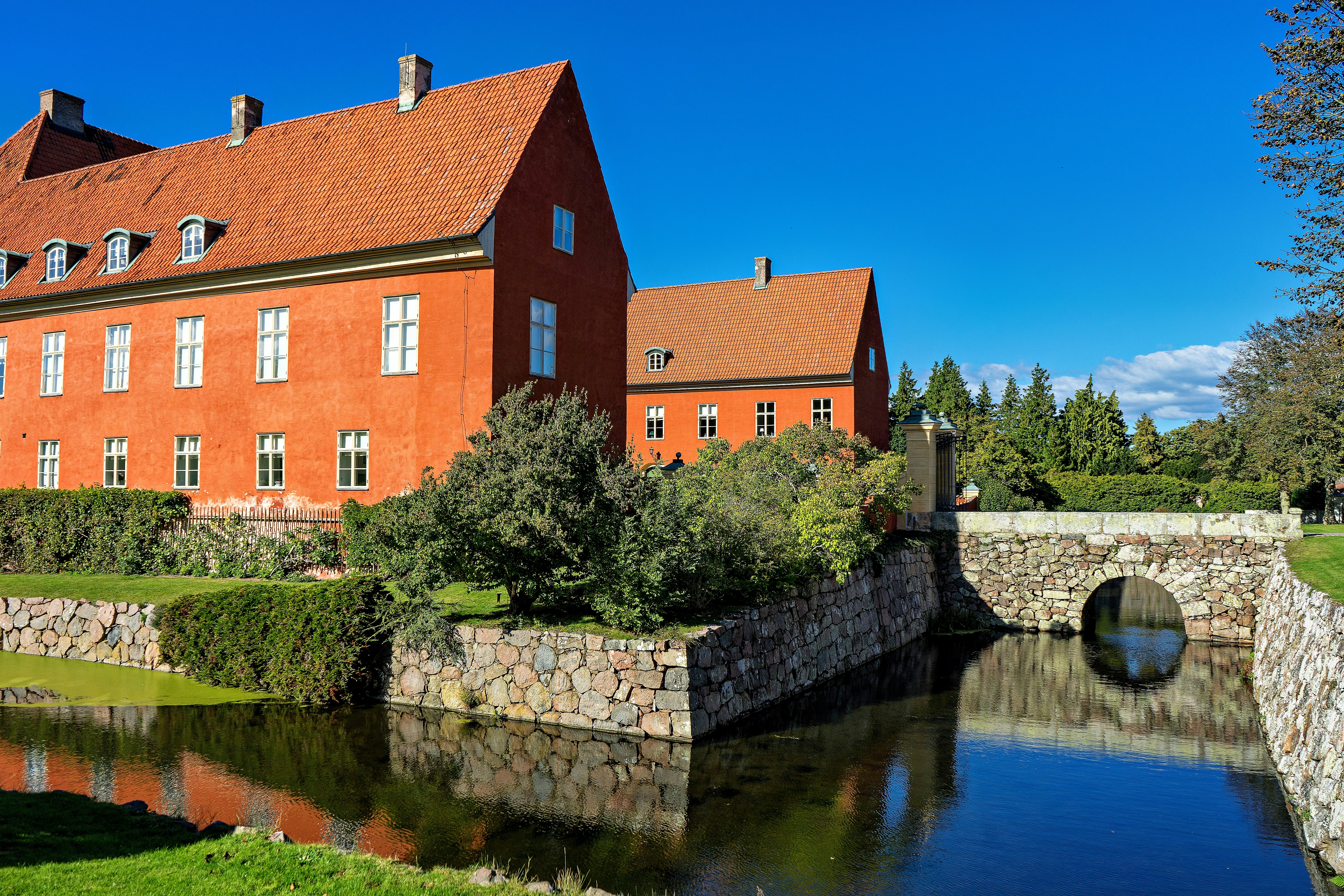 Krapperups castle | Historic red castle with moat and stone bridge.