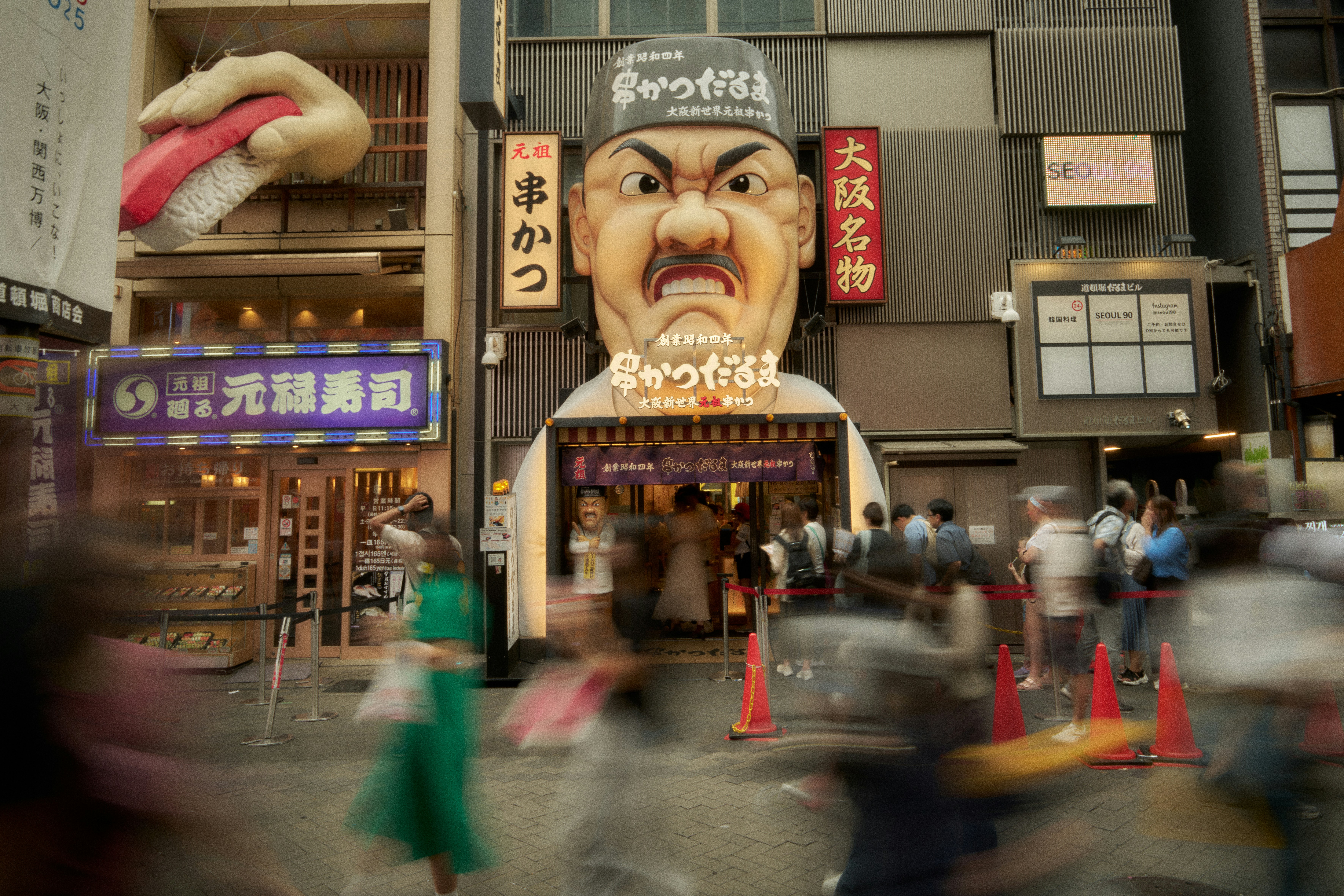 Giant angry face sign above busy street entrance