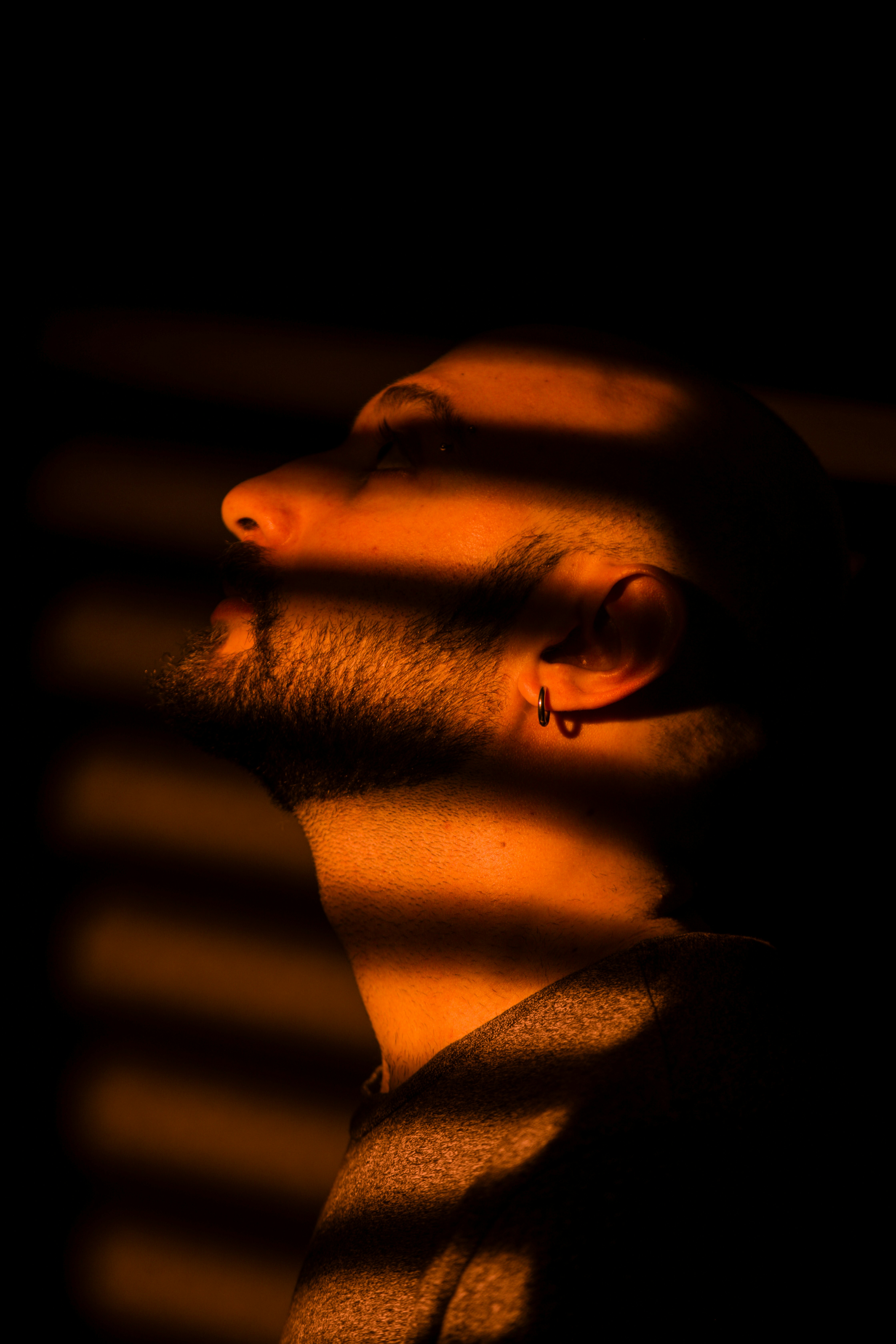 Looking up into the light. | Man illuminated by warm light through blinds