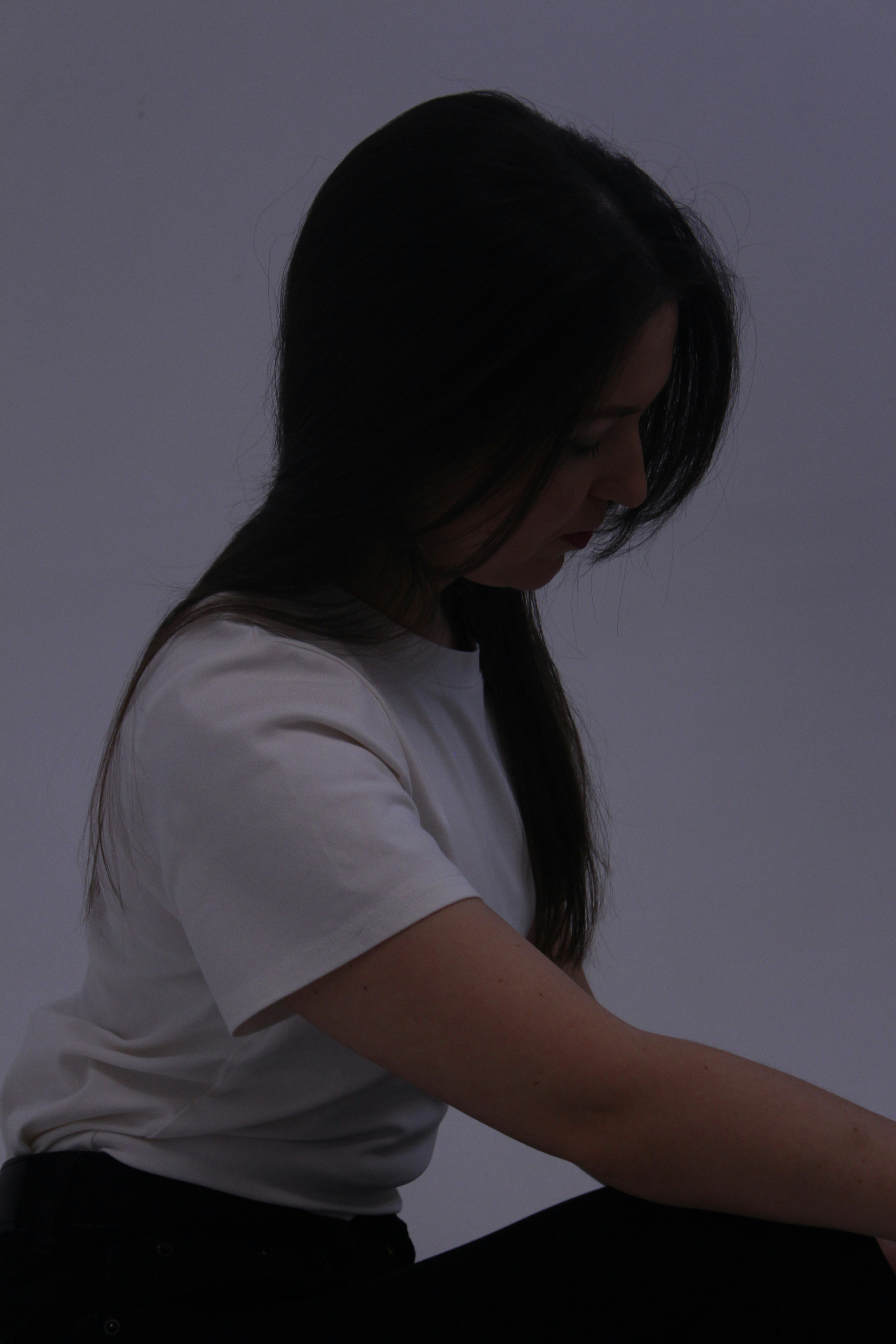 A young woman with dark hair looking down