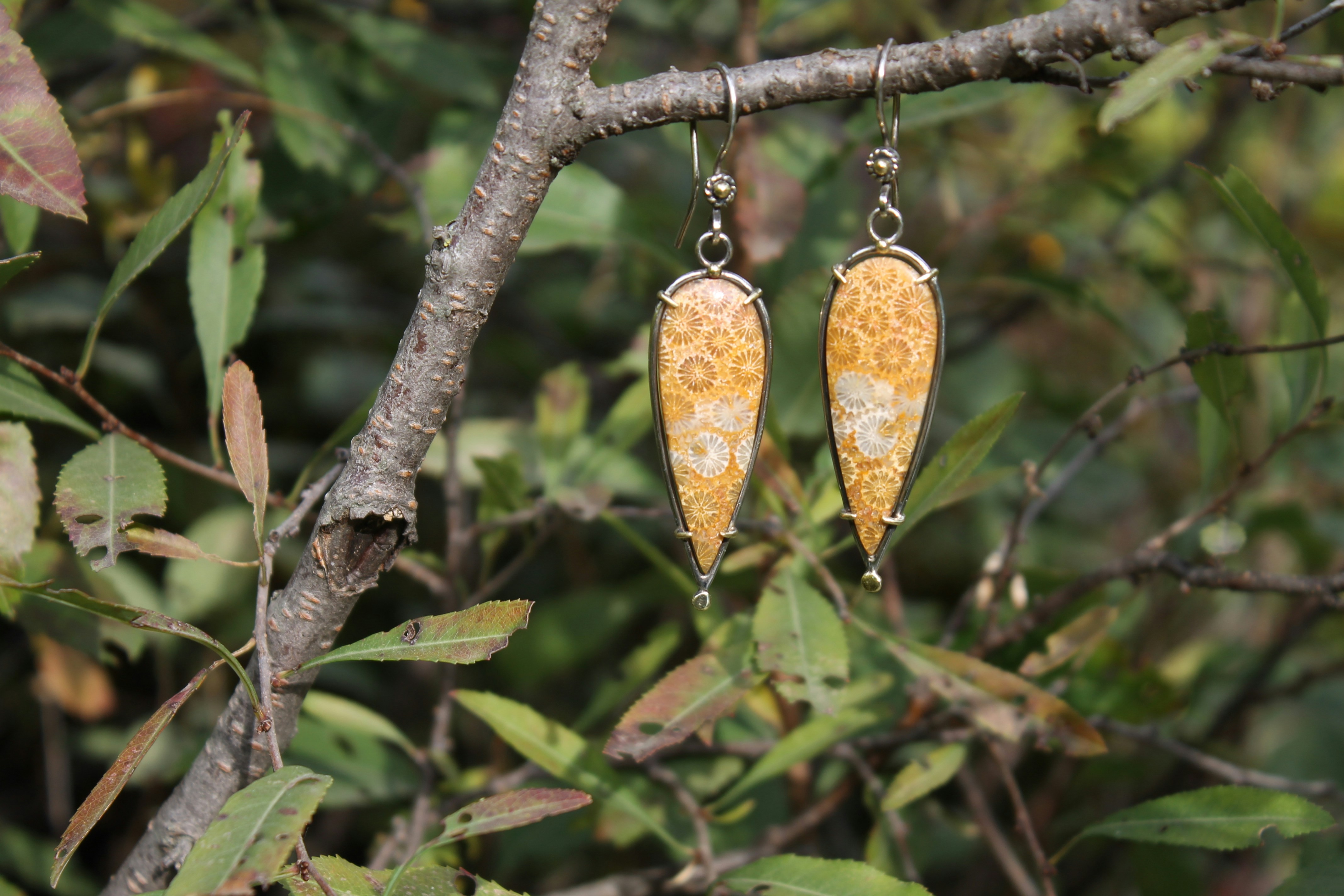 Gold-Patterned Teardrop Earrings Dangle in a Quiet Green Canopy