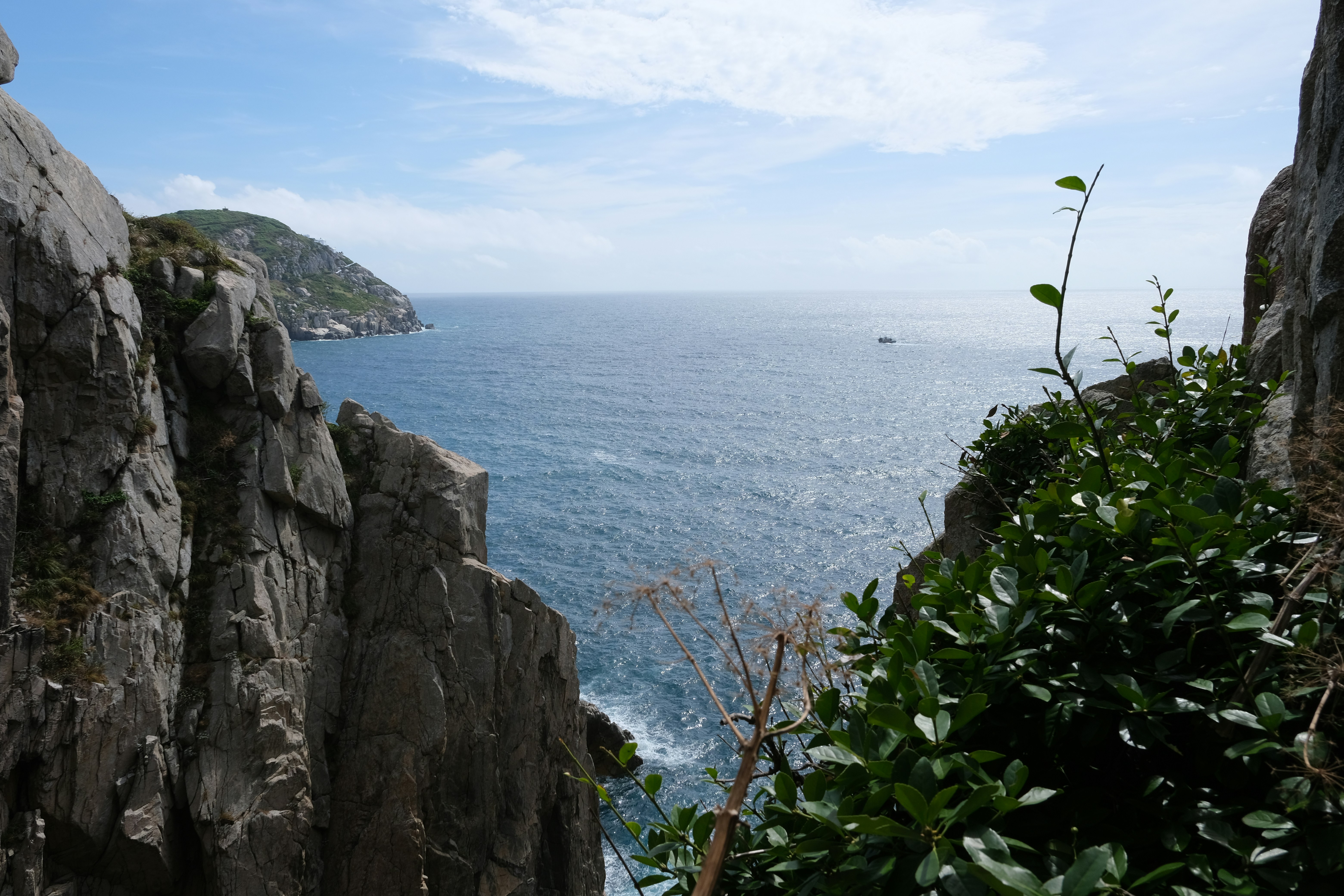 Rocky cliffs framing a calm blue ocean under sky.