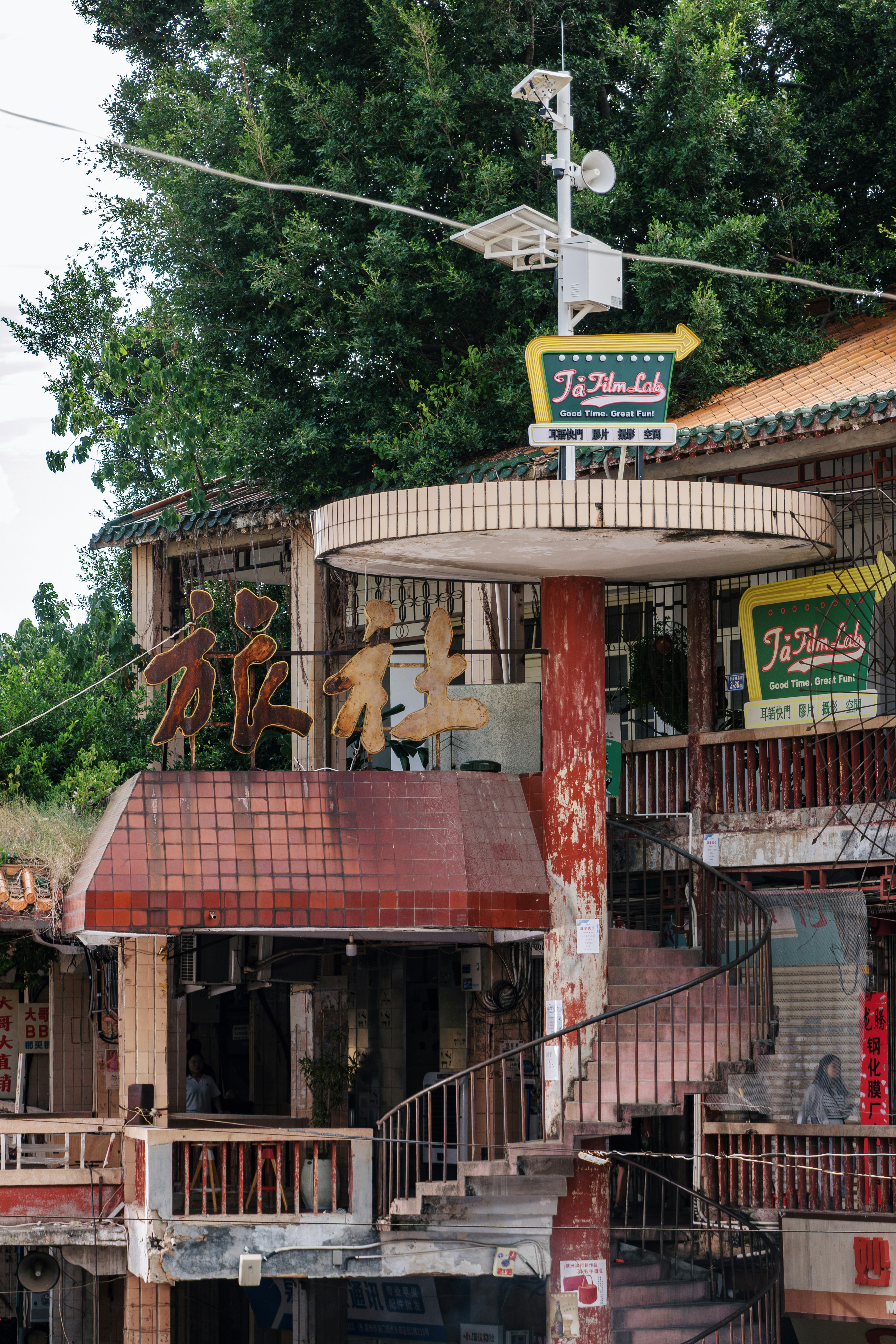 Curved Staircase and Gold Characters: A Weathered Facade Under a Green Canopy