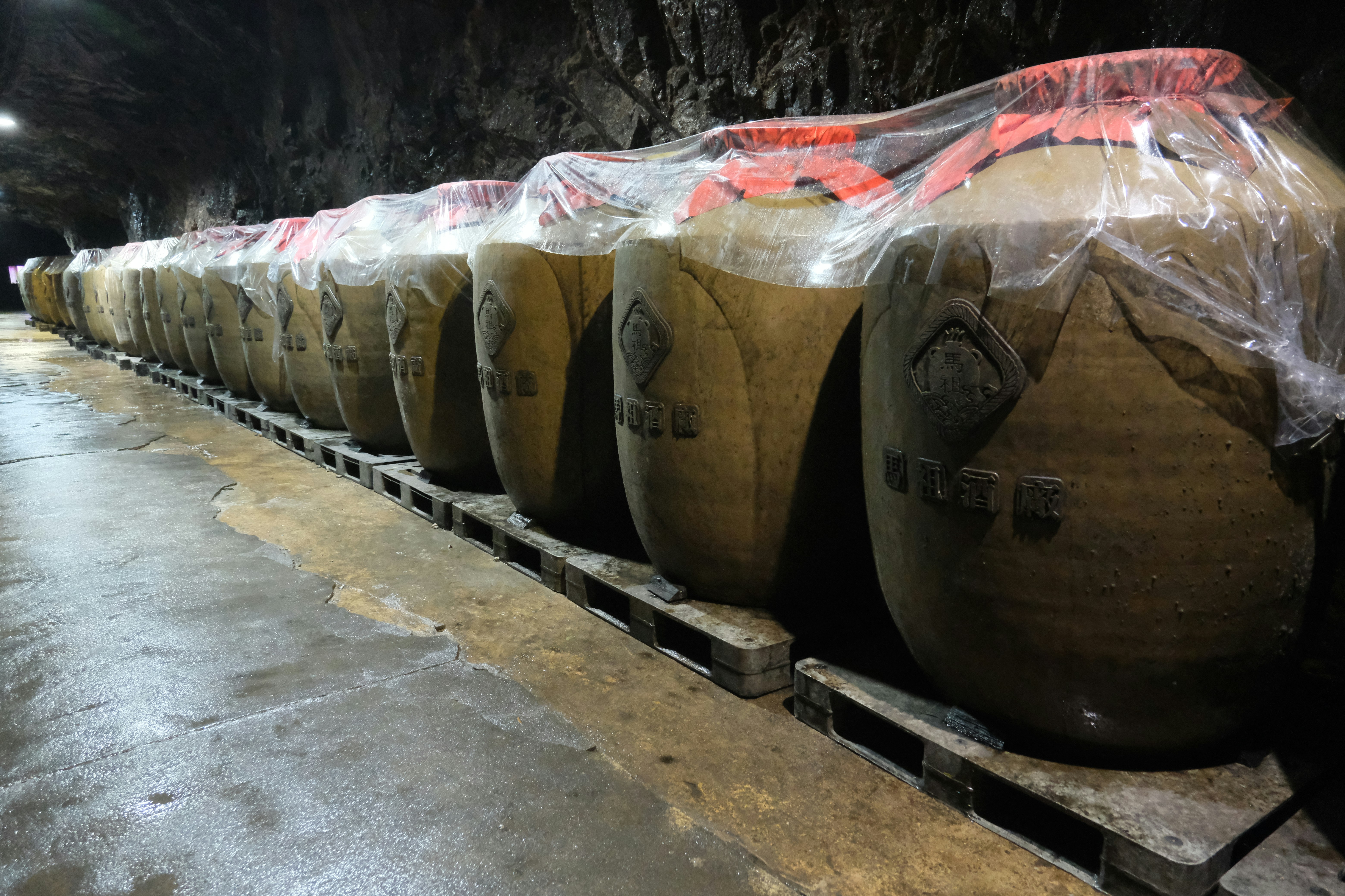 Large ceramic jars lined up in a dark cellar