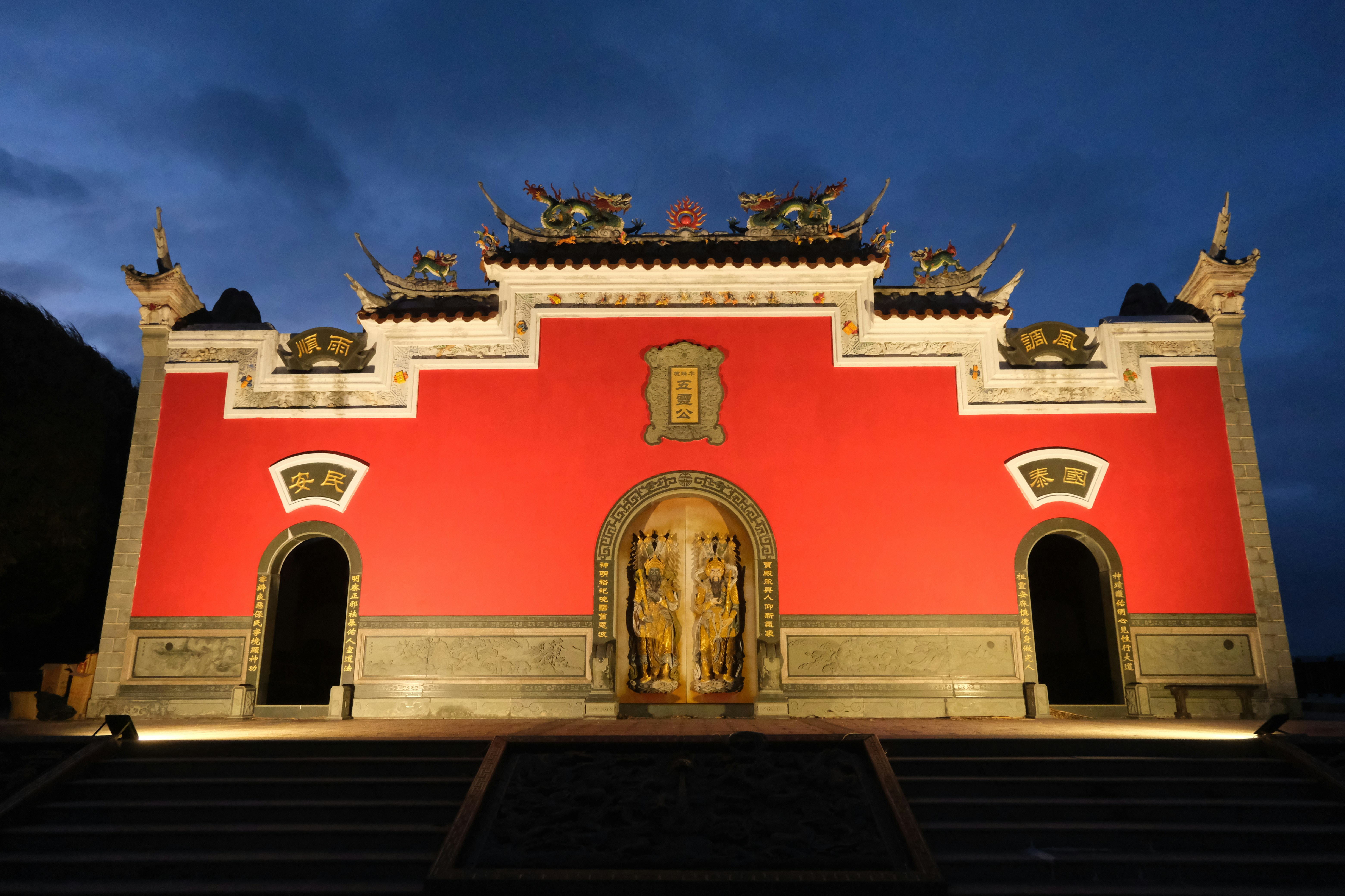 Ornate red temple entrance with golden doors at dusk