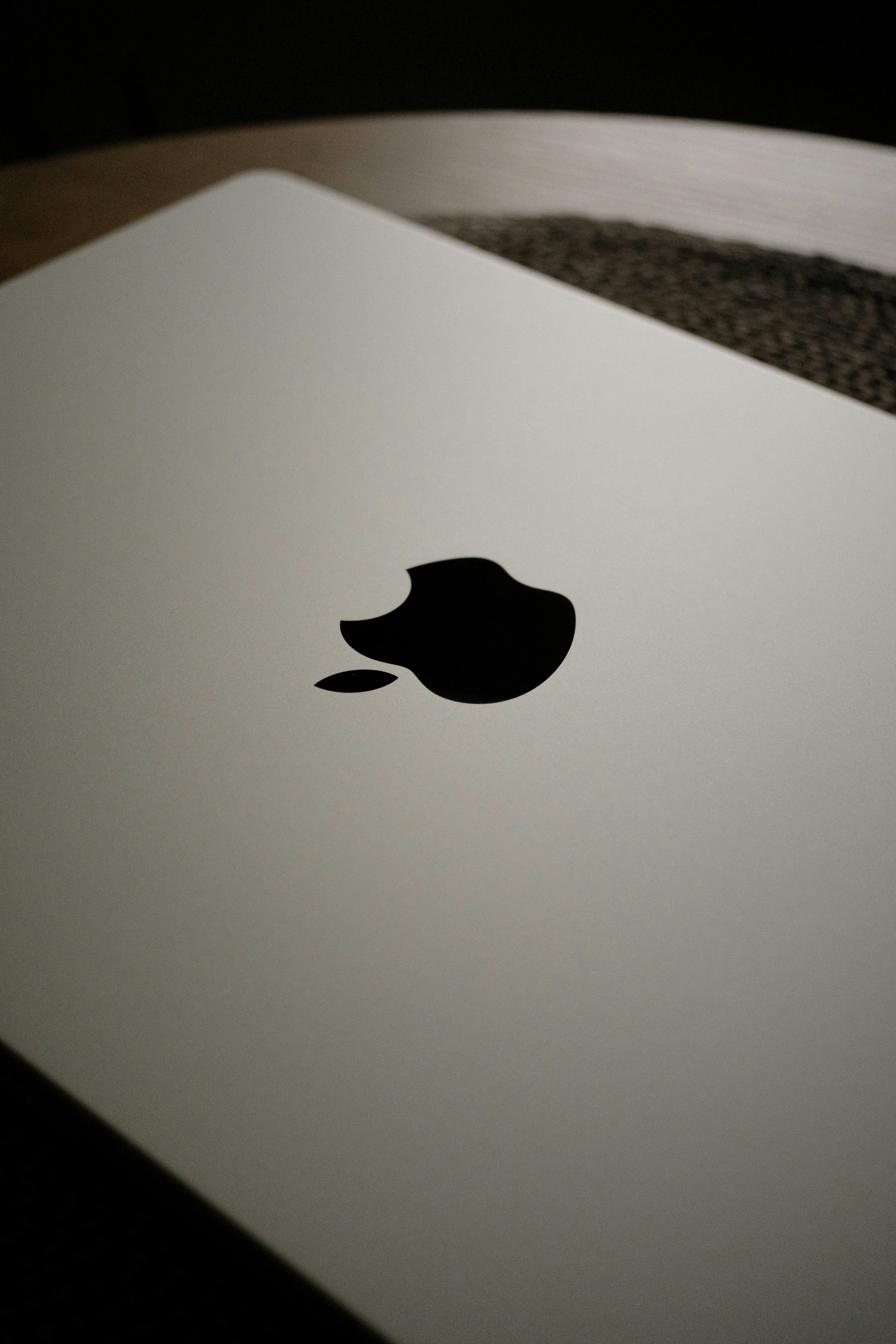 Close-up of a MacBook's iconic logo against a soft, neutral background, showcasing its elegant simplicity.