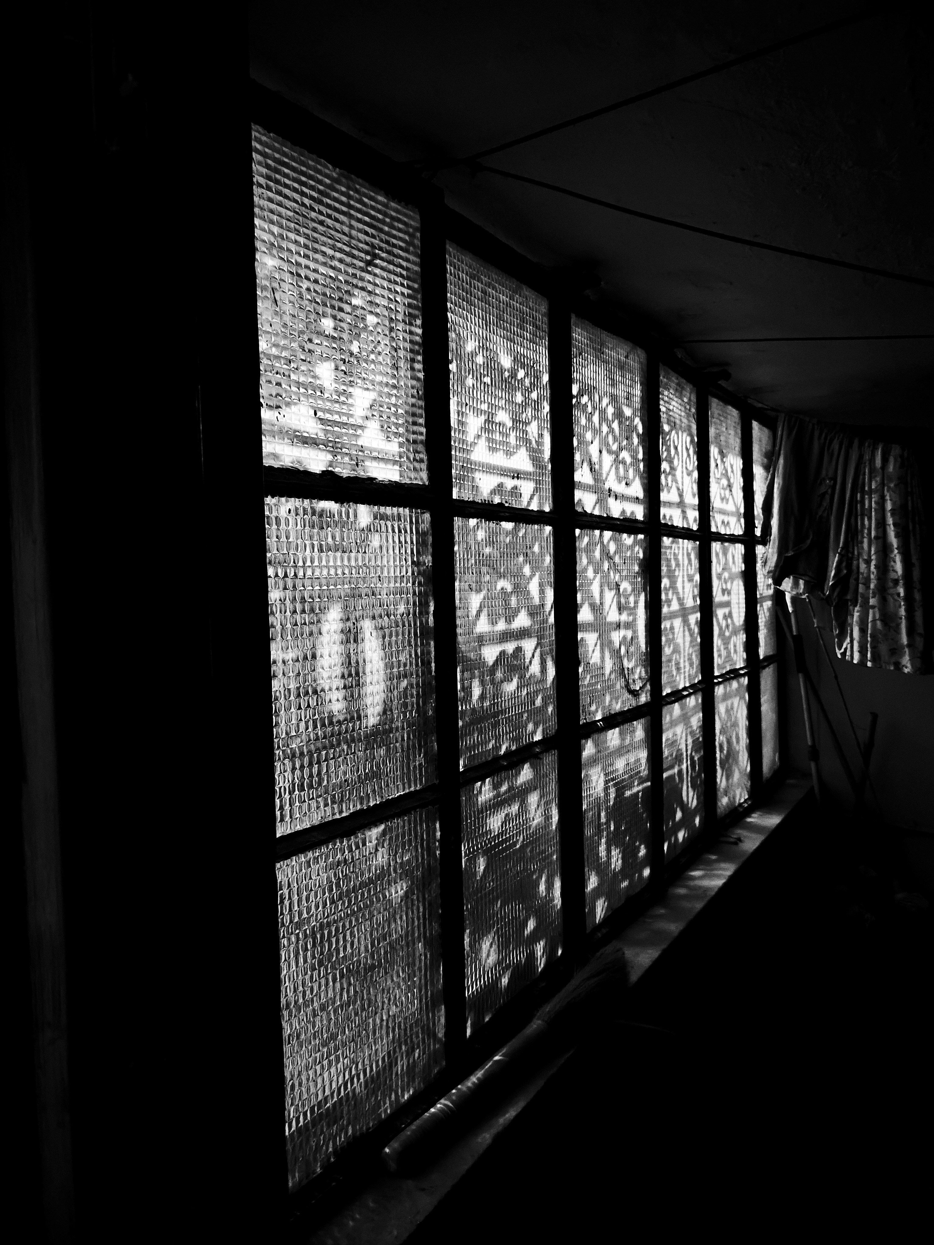 Sunlight streams through a patterned window creating shadows.