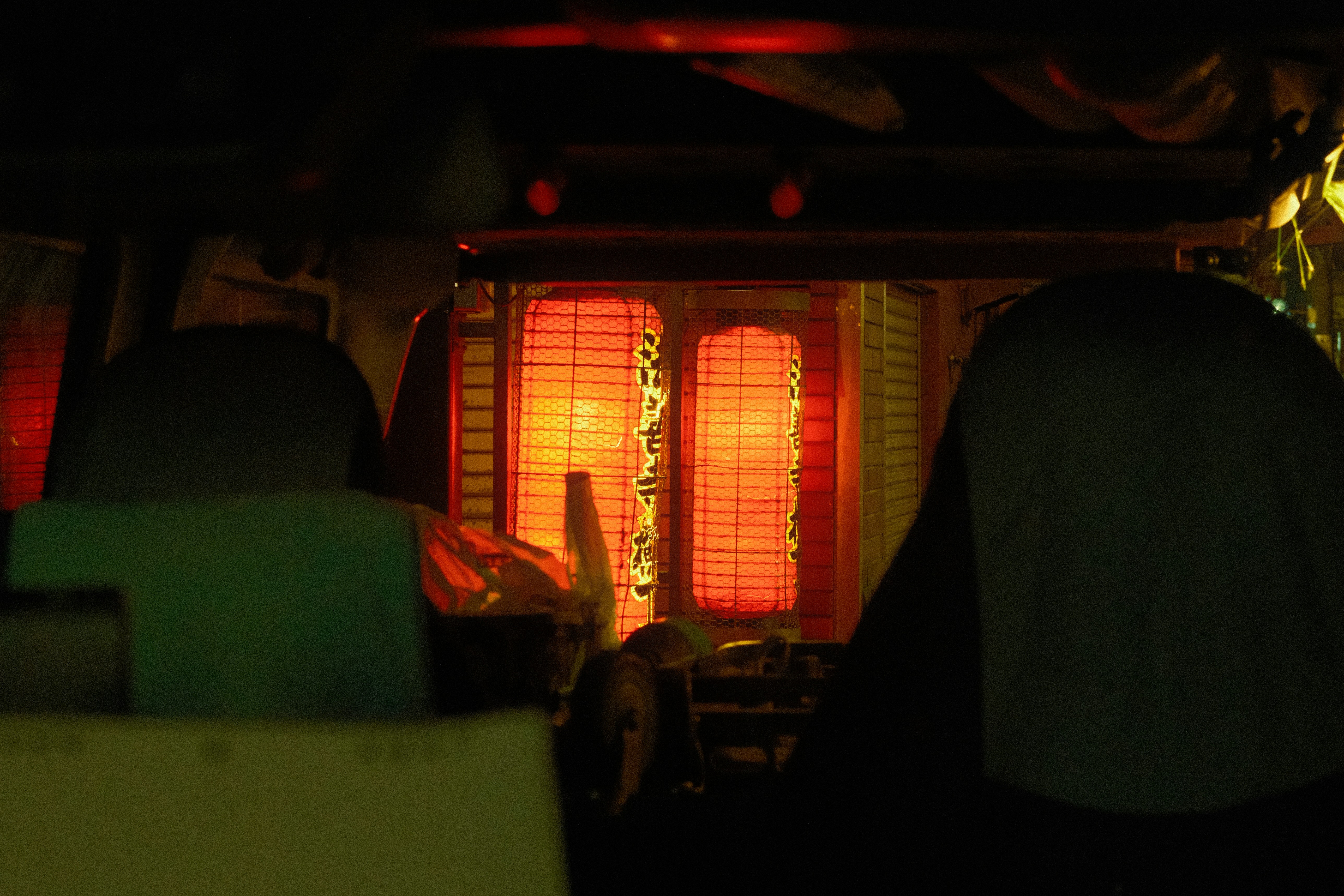Dimly lit interior of a vehicle showcasing glowing red lights through a window, creating a moody ambiance.