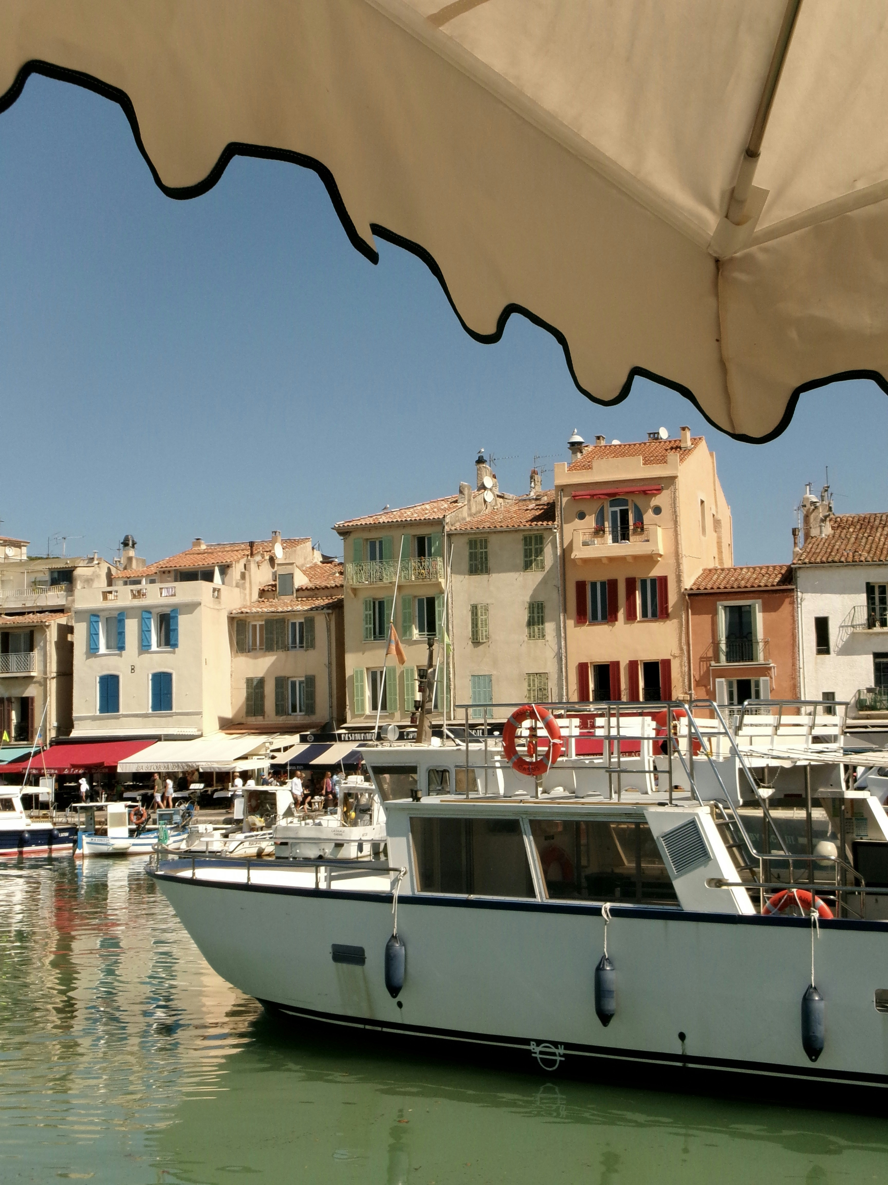 Vibrant waterfront scene featuring colorful buildings and moored boats under a bright sky. The image captures the essence of a lively coastal town.