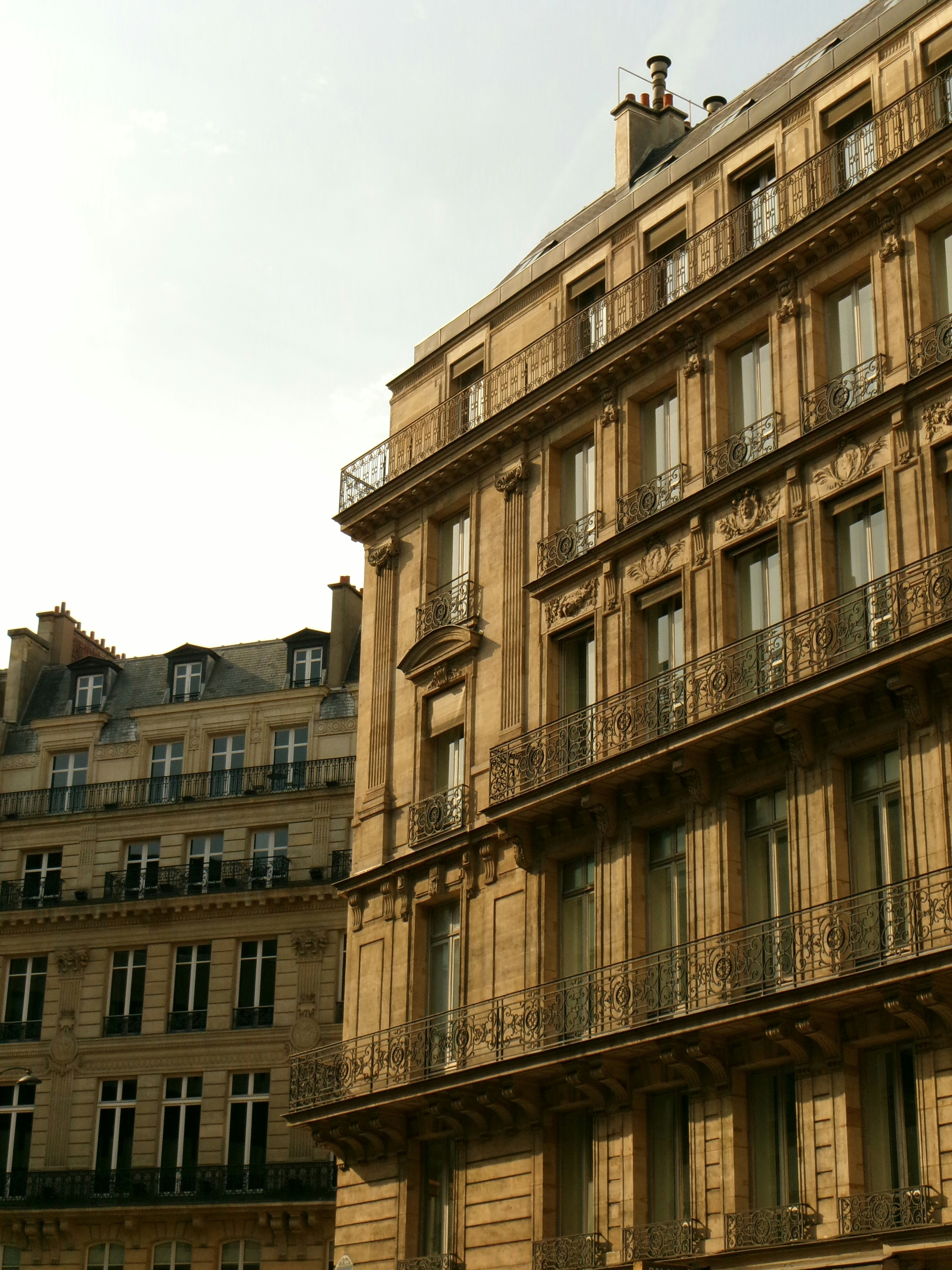 Historic Parisian buildings showcasing intricate façades and ornate balconies under a soft evening glow.