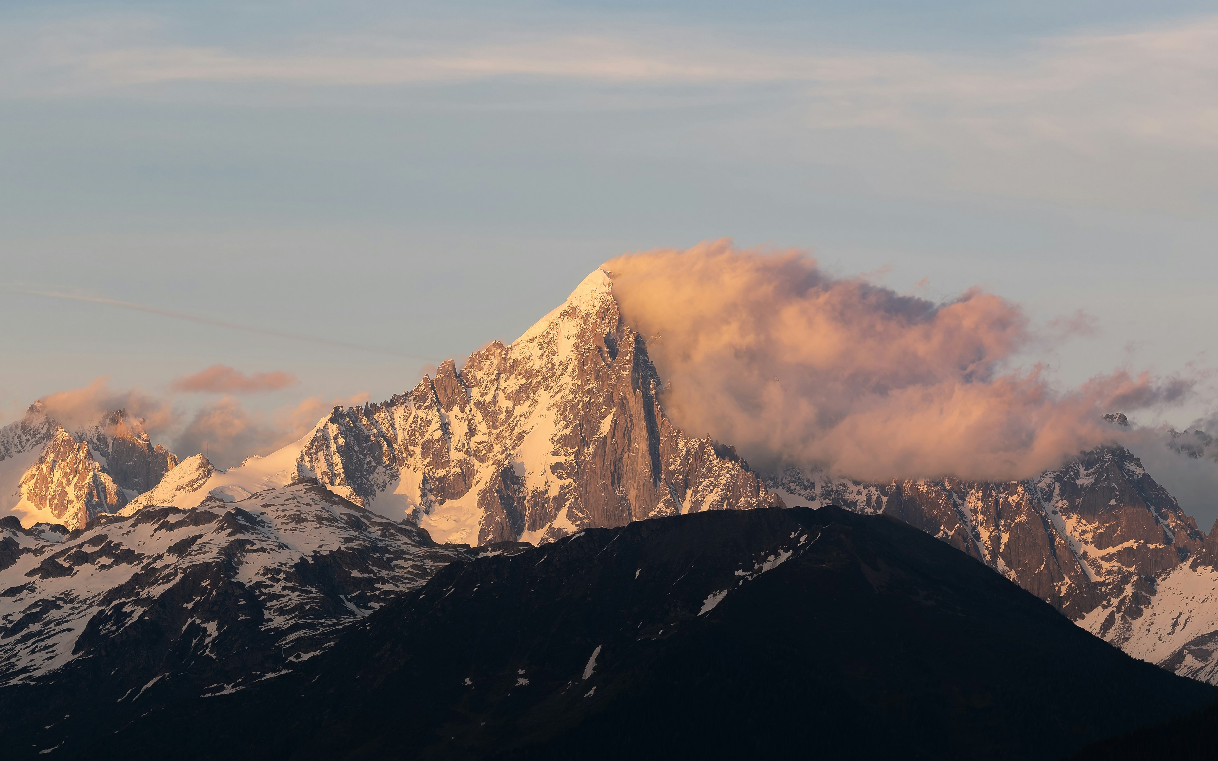Snow-capped mountain peak illuminated by sunset light.