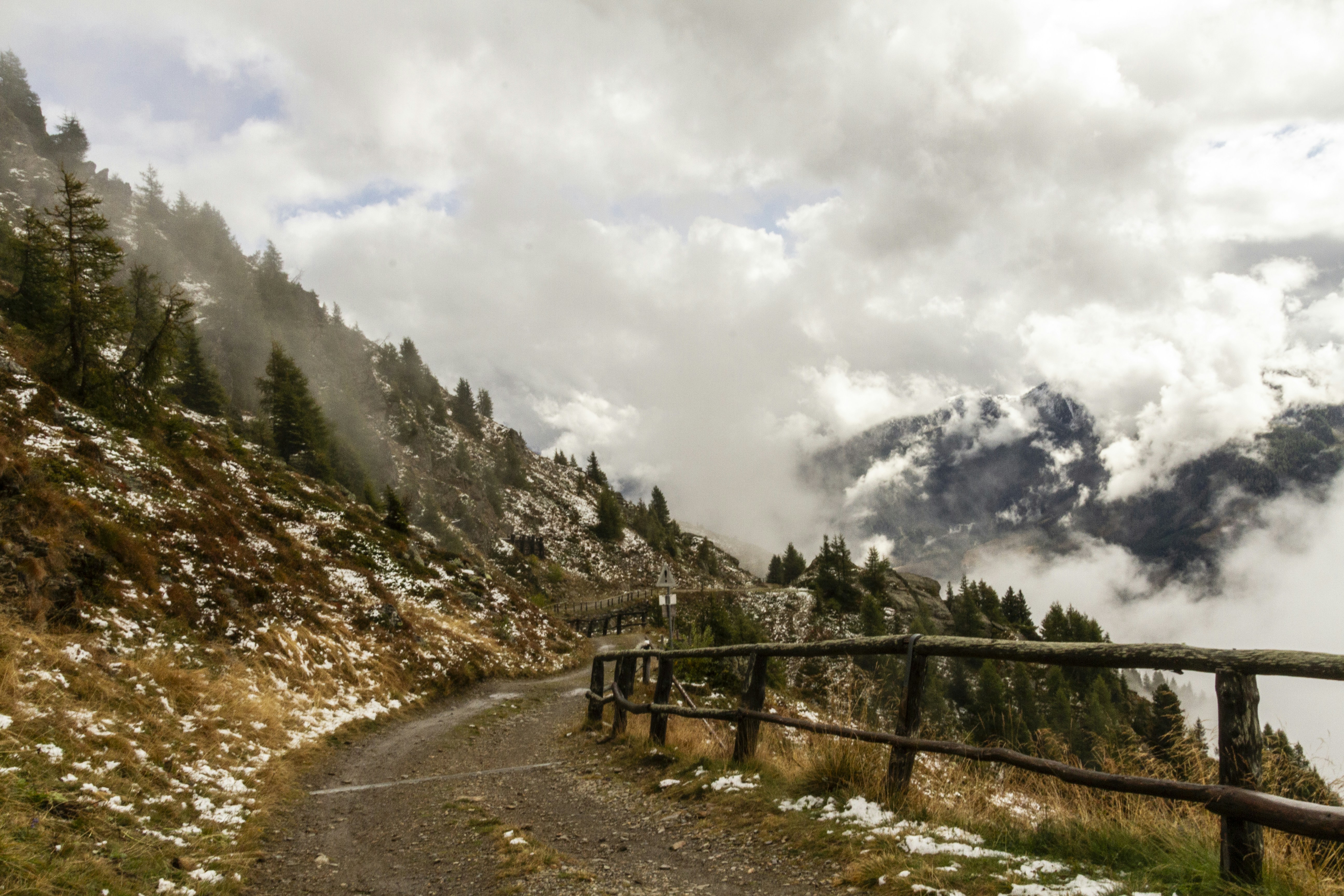 Mountain path with wooden fence and cloudy sky