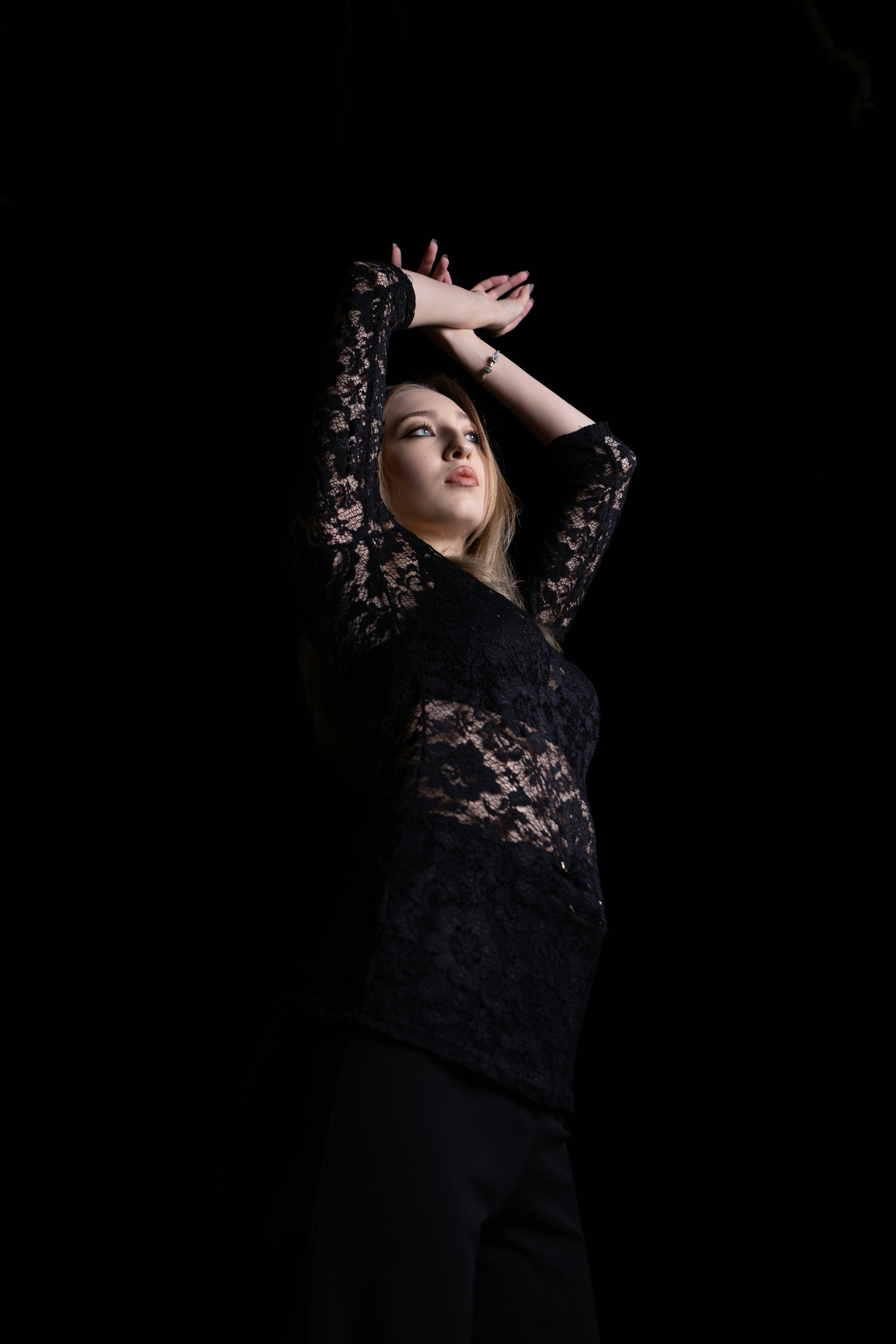 Woman in black lace top with arms raised