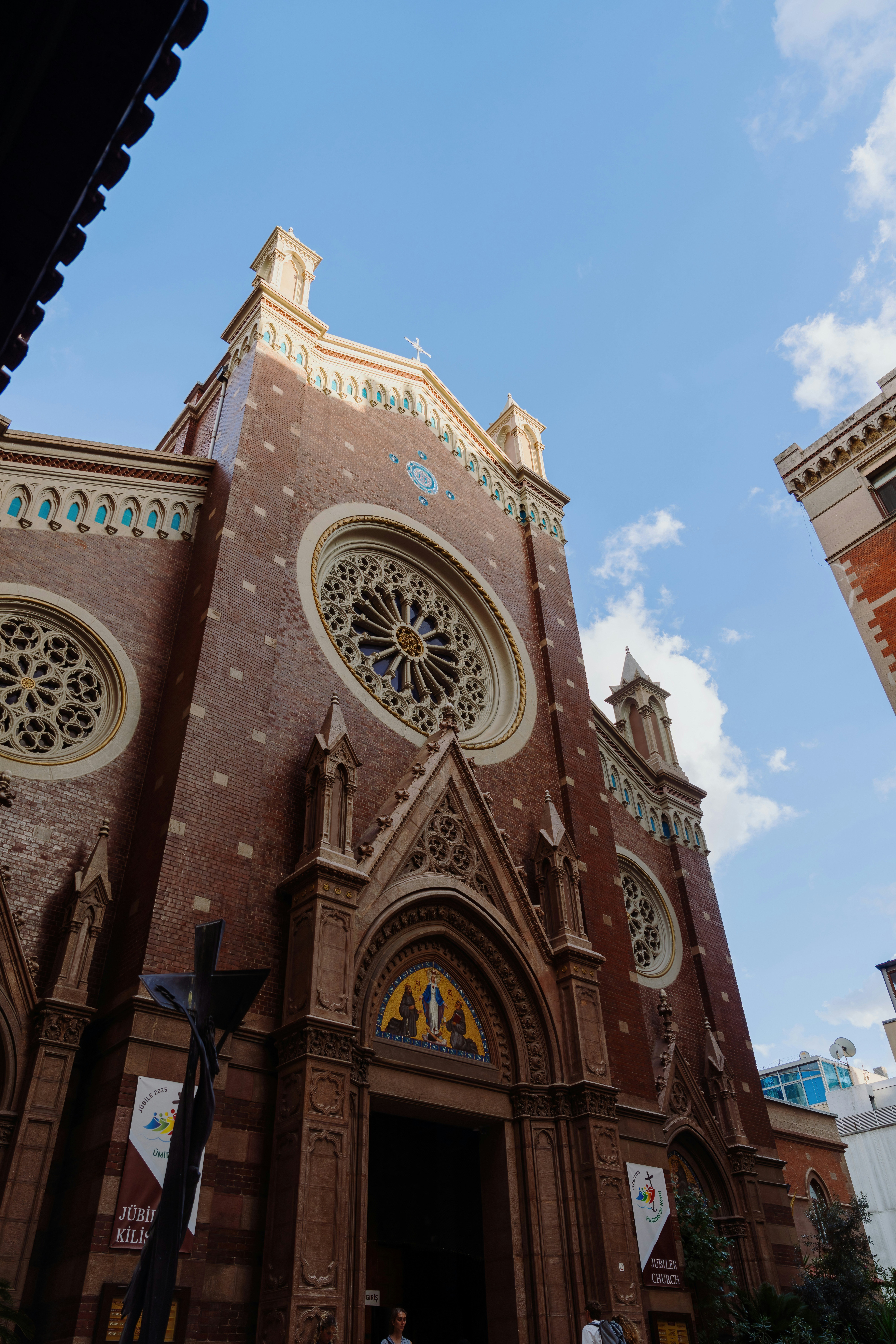 Intricate facade of a historic church featuring ornate details and large stained glass windows under a blue sky.
