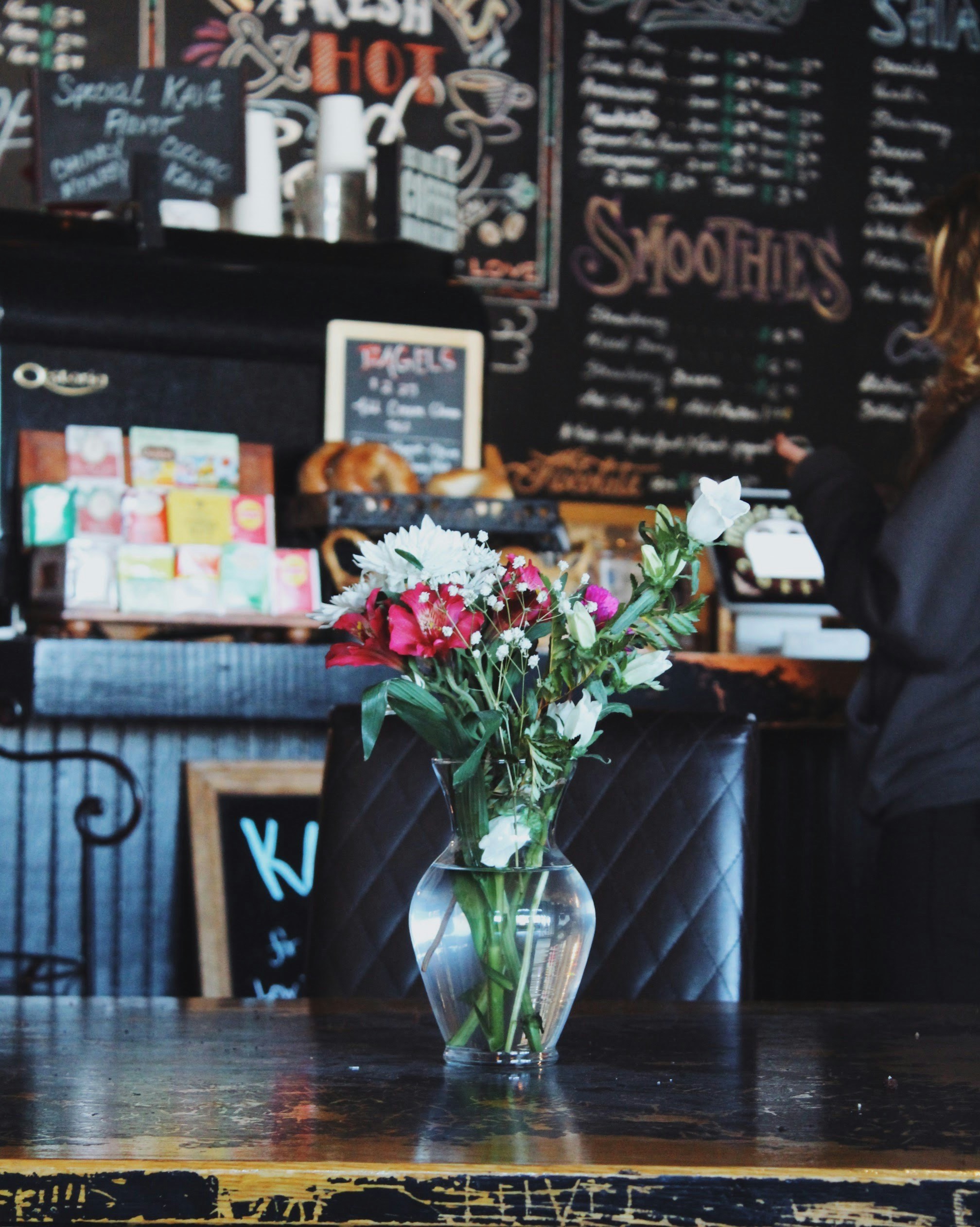 Vase of flowers on a wooden table in cafe.
