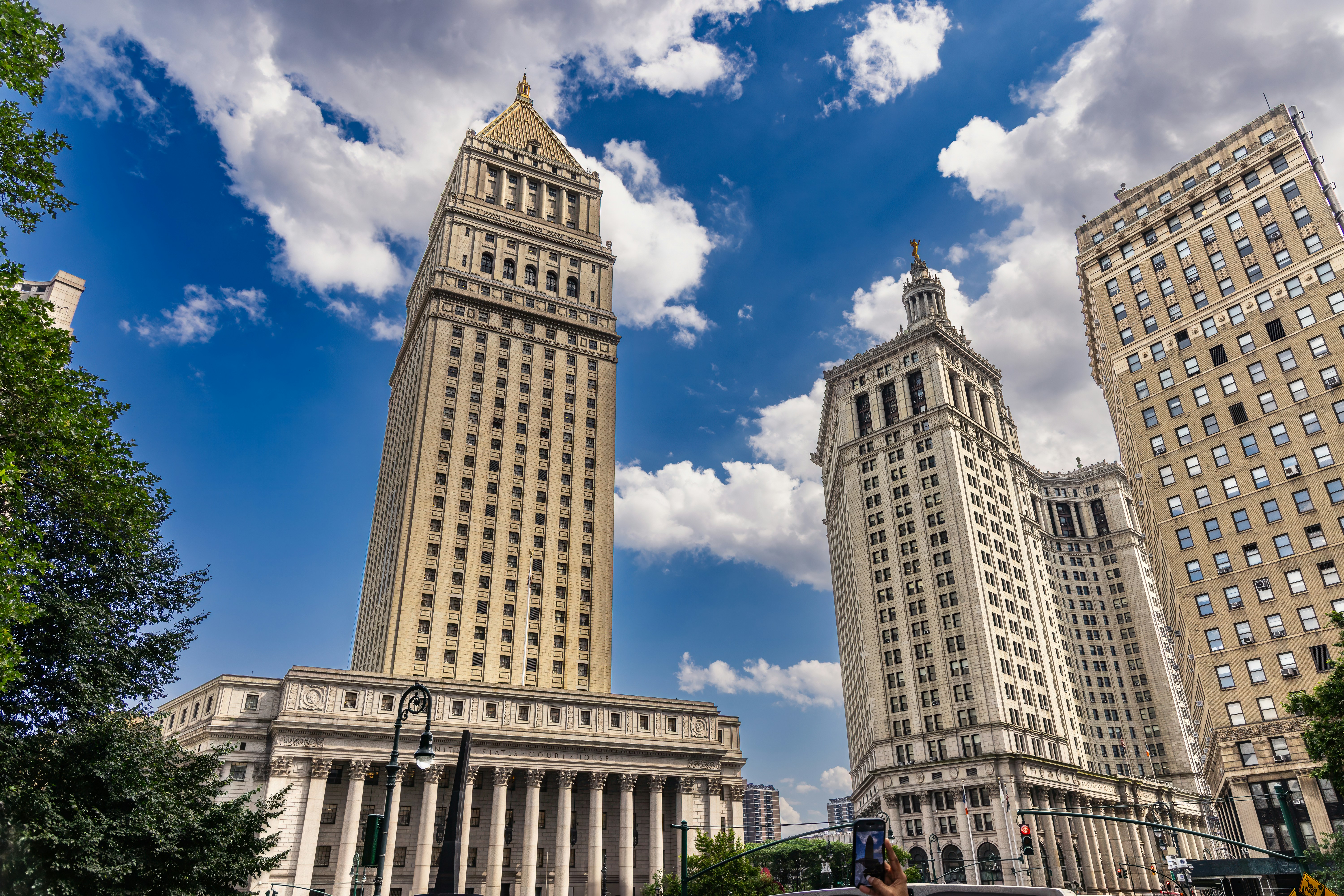 The Thurgood Marshall United States Courthouse (originally the United States Courthouse or the Foley Square Courthouse) is a 37-story courthouse at 40 Centre Street on Foley Square in the Civic Center neighborhood of Lower Manhattan in New York City, United States. | Tall buildings against a blue sky with clouds