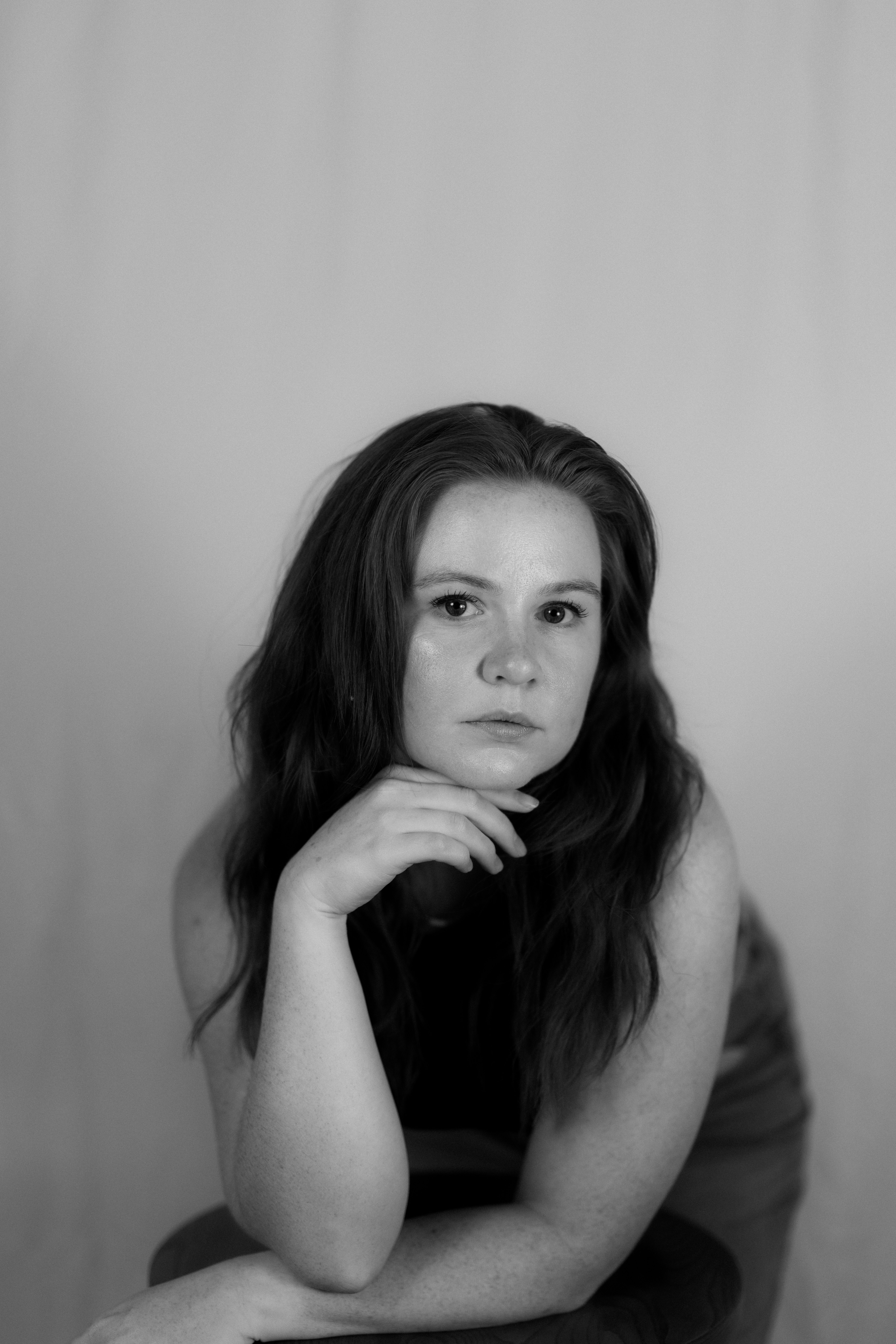 A young woman rests her chin on her hand.
