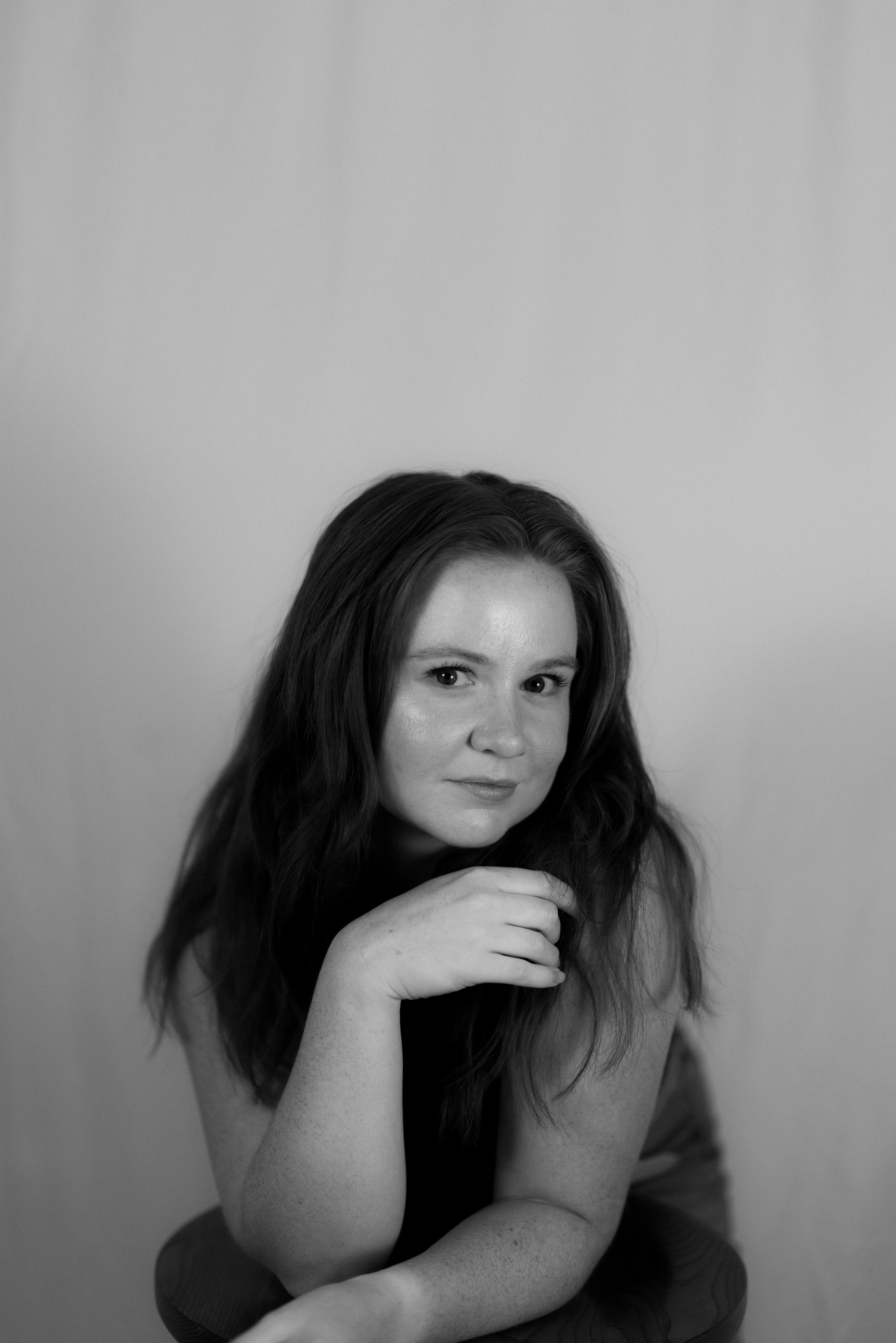Young woman with long hair resting chin on hand