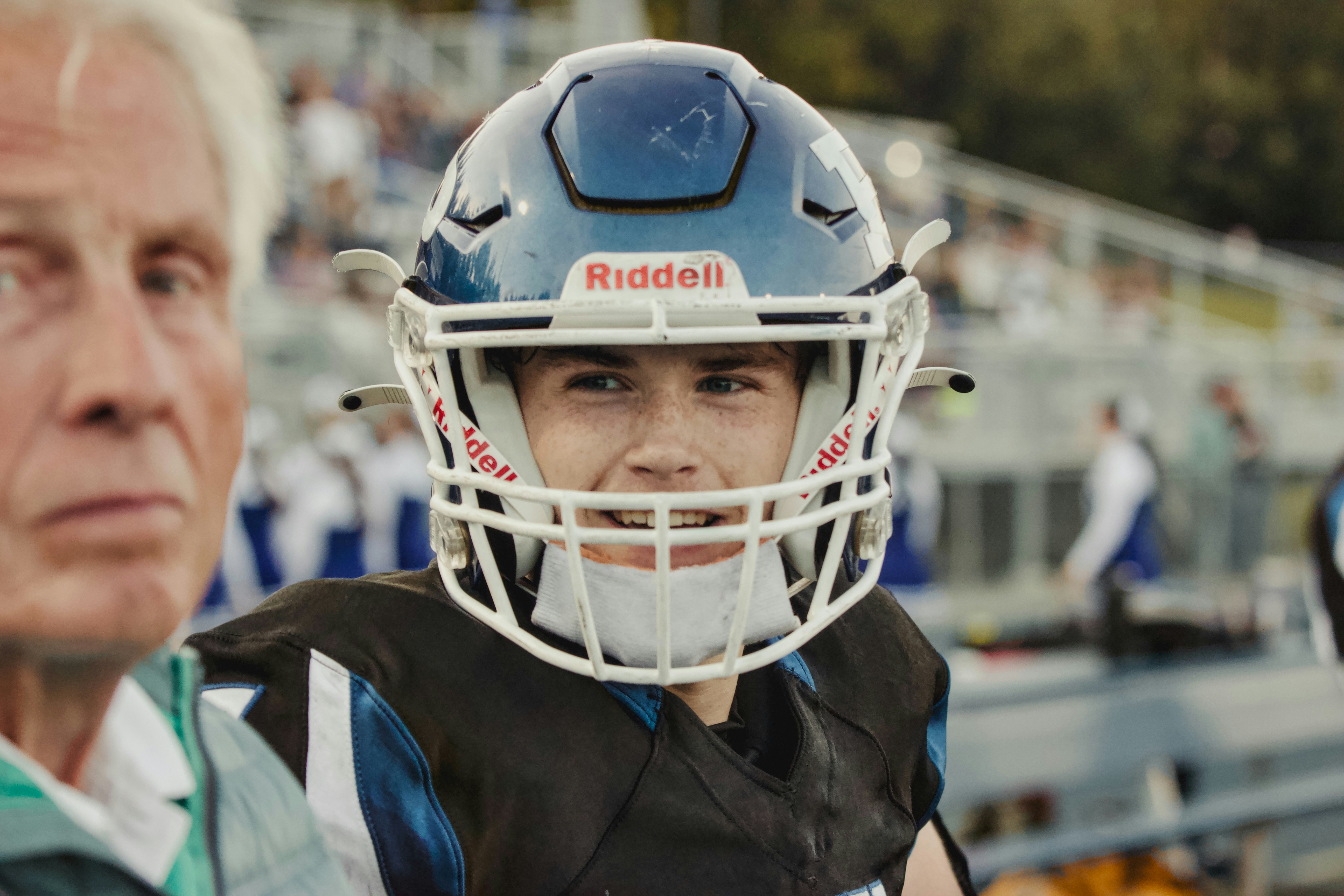 Young football player in helmet with coach watching