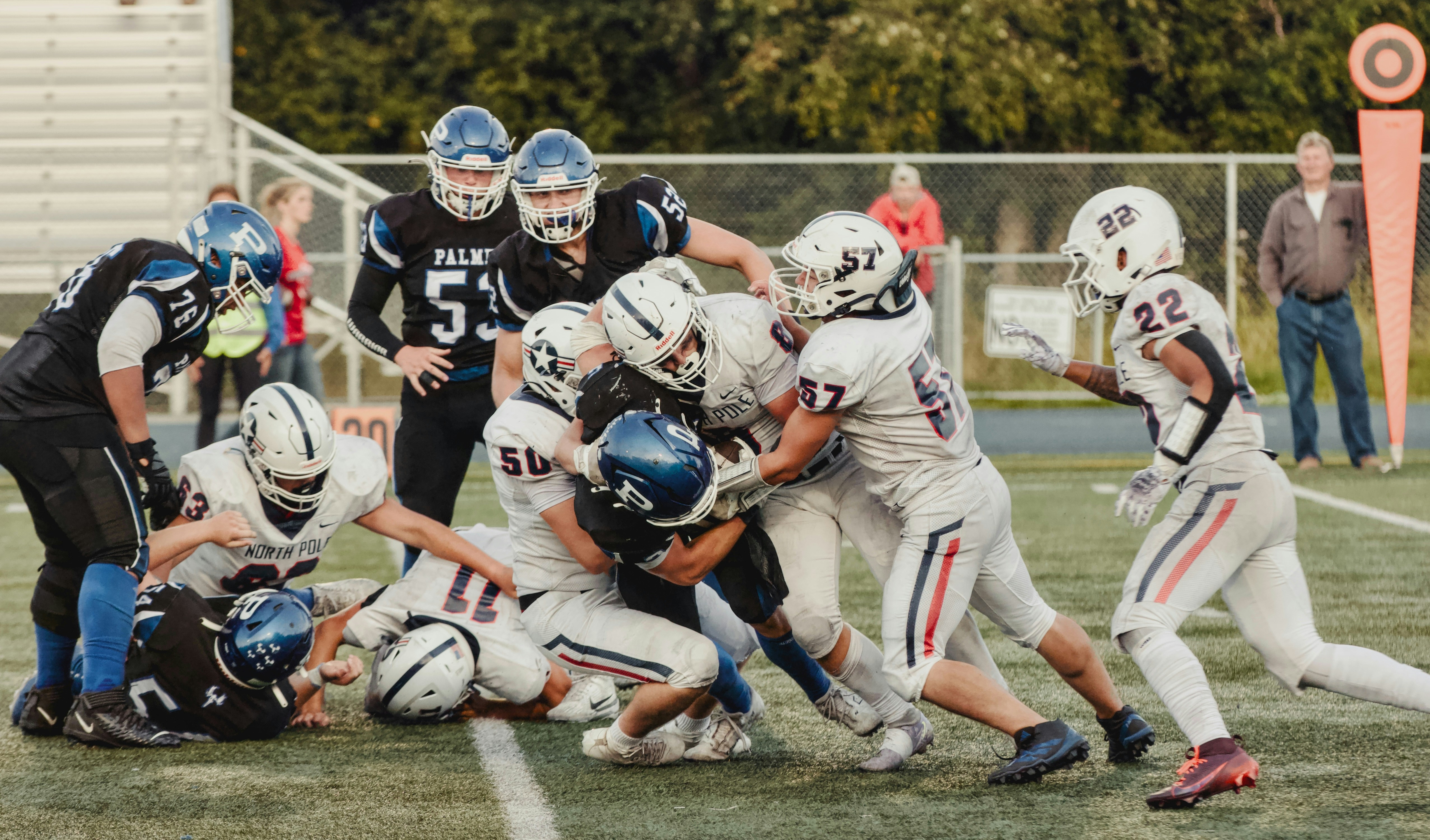 A dynamic football play unfolds as players from both teams engage in a fierce tackle on the field, showcasing athleticism and teamwork.