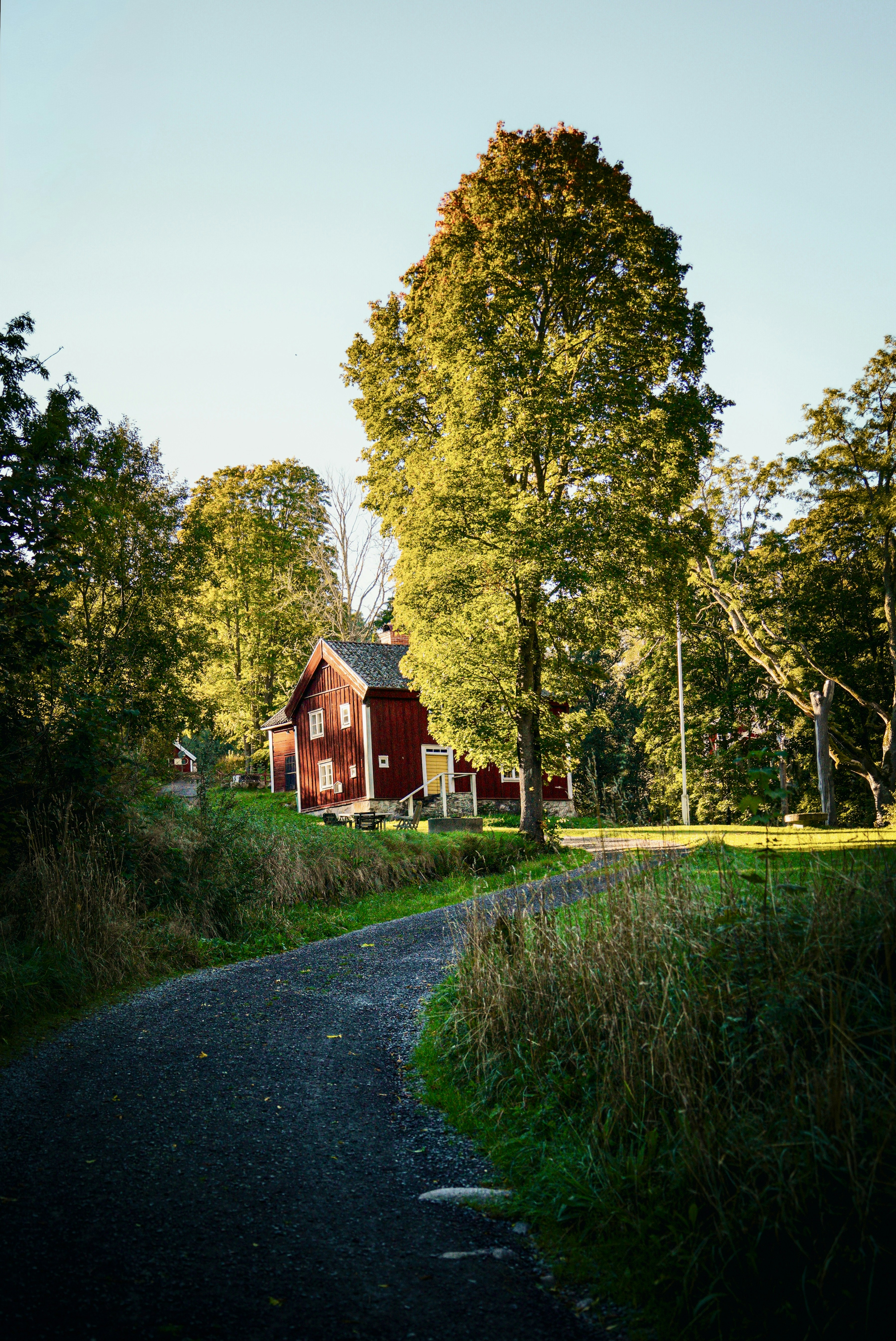 Red house nestled among trees with a winding path.