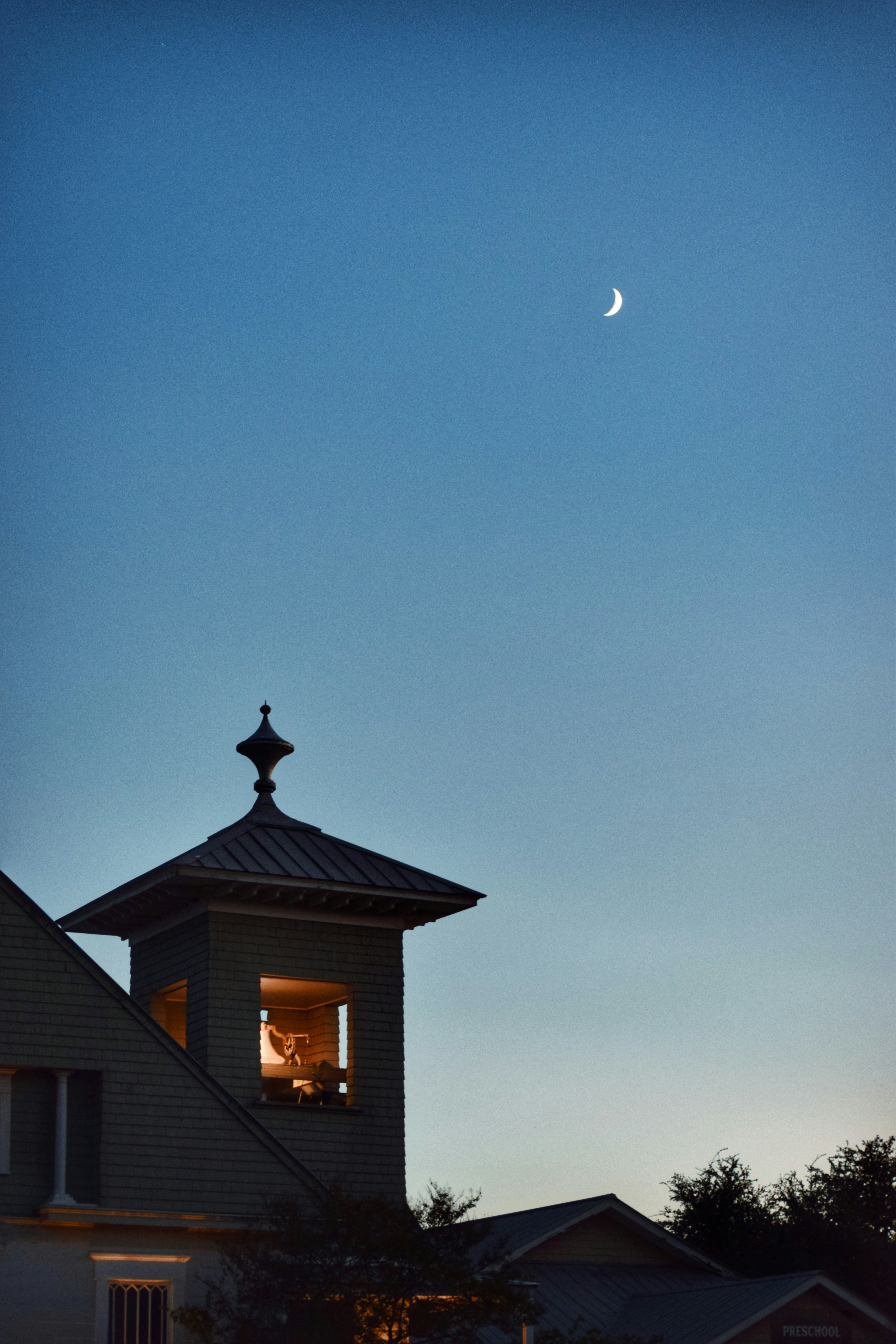 Methodist Church Bell Tower over a clear evening sky with crescent moon. Great Oaks Drive, Round Rock, Texas, September 2025. | Crescent moon over a building at dusk