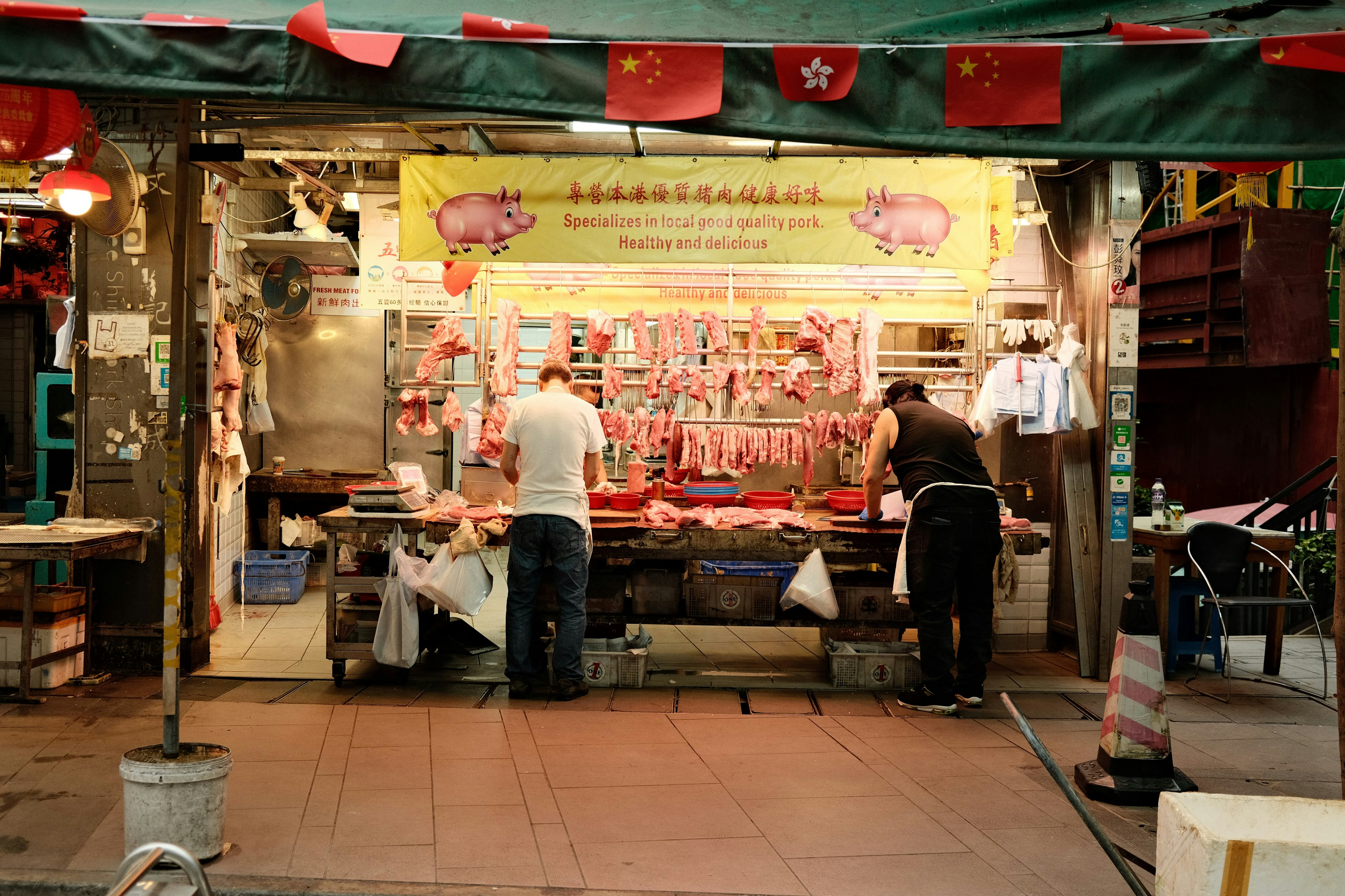 Butchers working at a meat stall in a market.