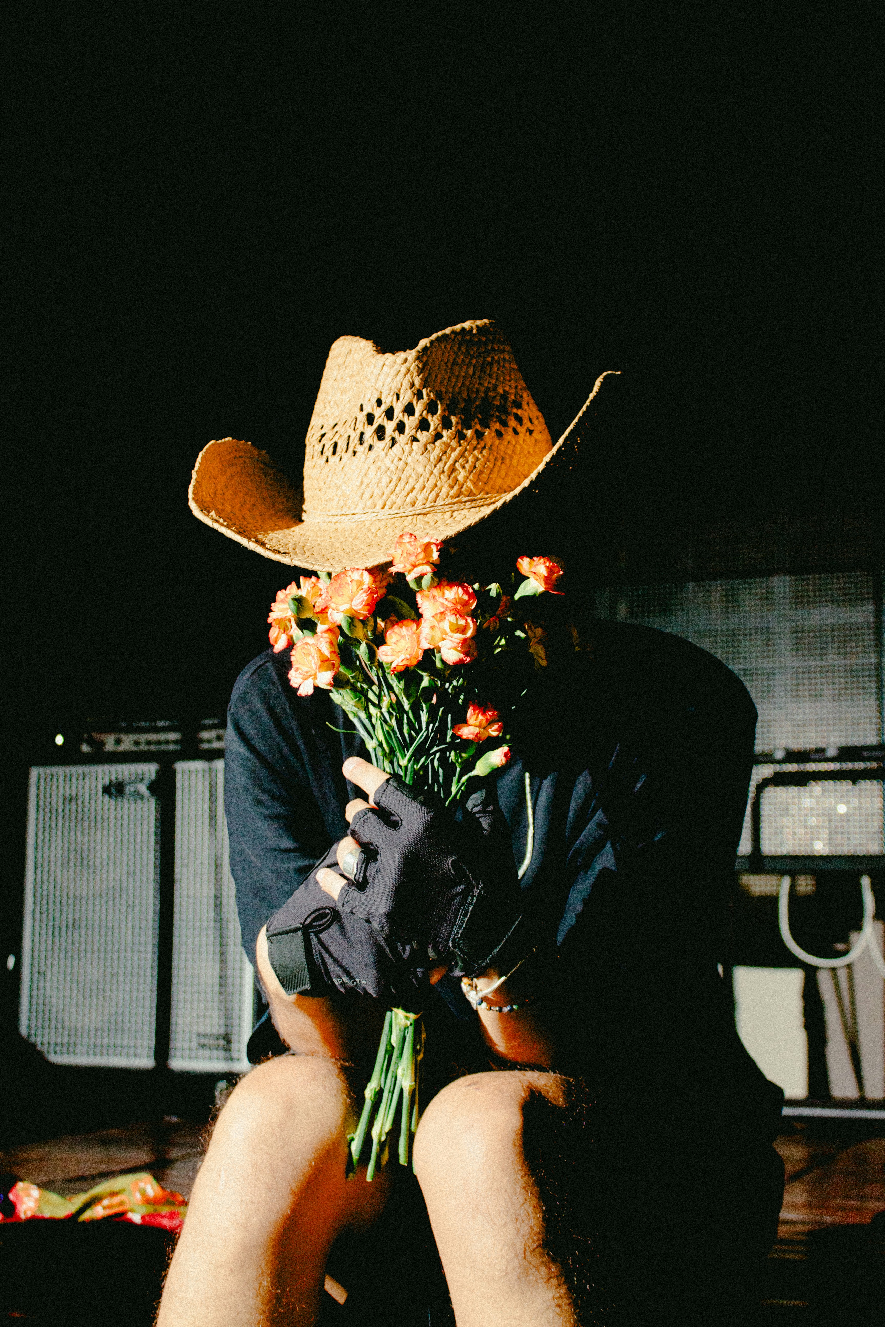 Person in cowboy hat holding orange flowers