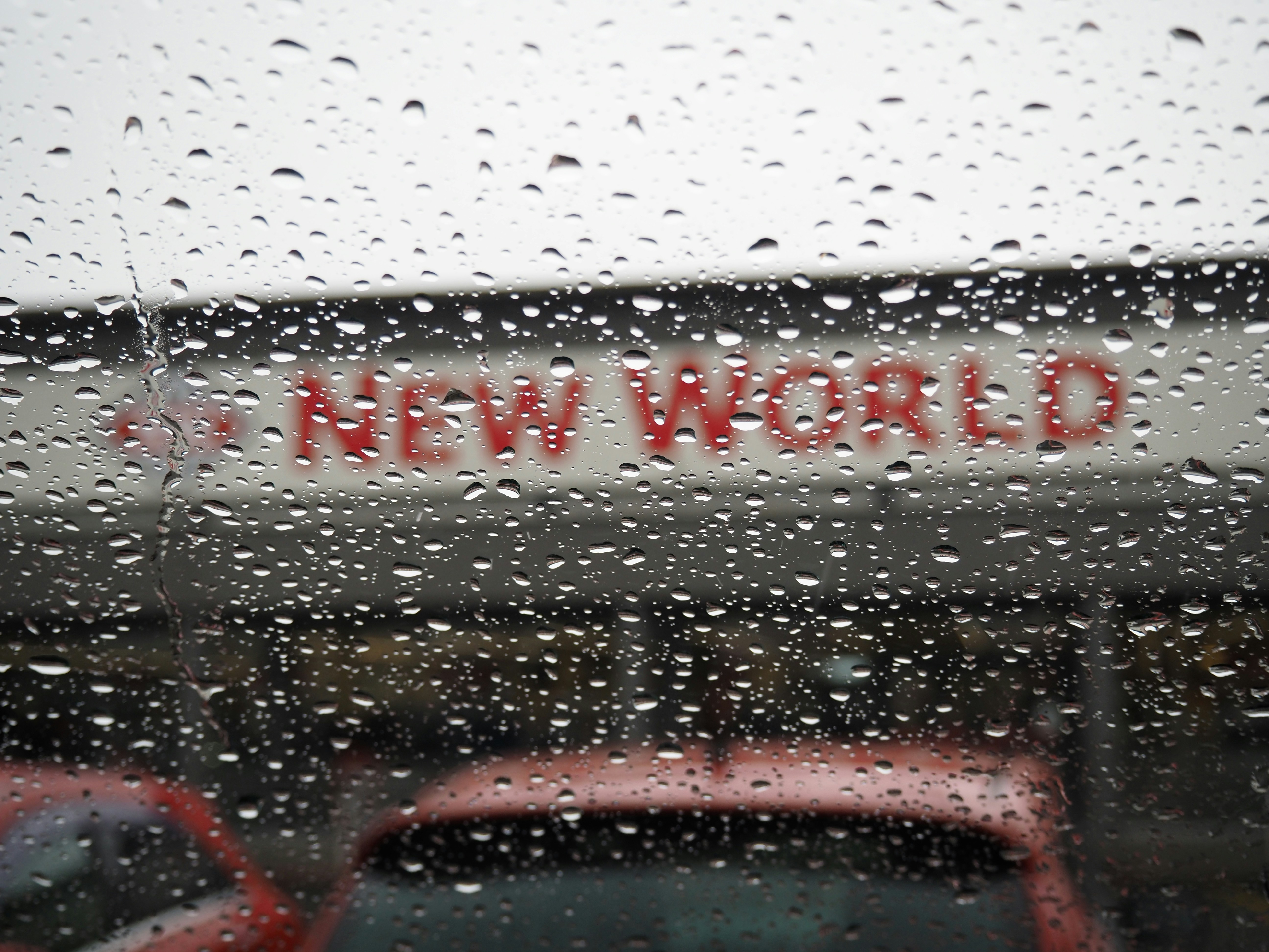 Raindrops on a window with "new world" sign.