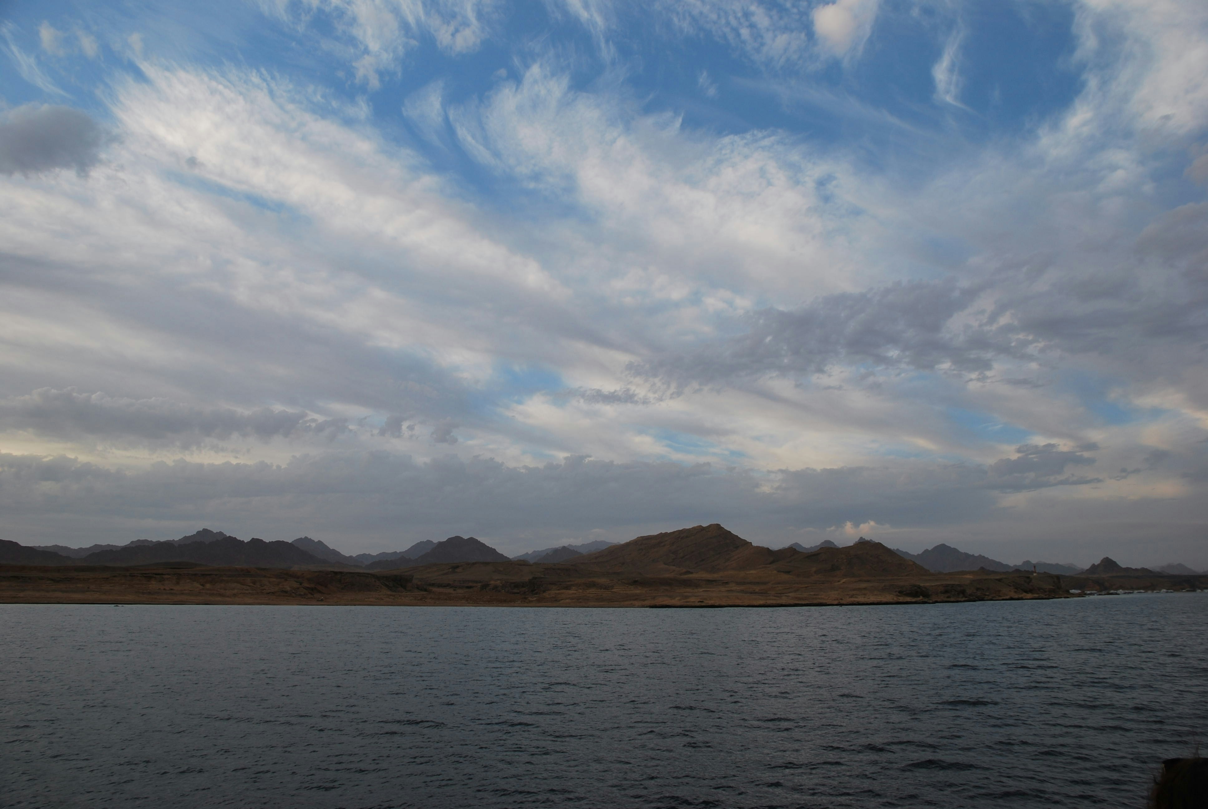 Calm water with mountains and cloudy sky