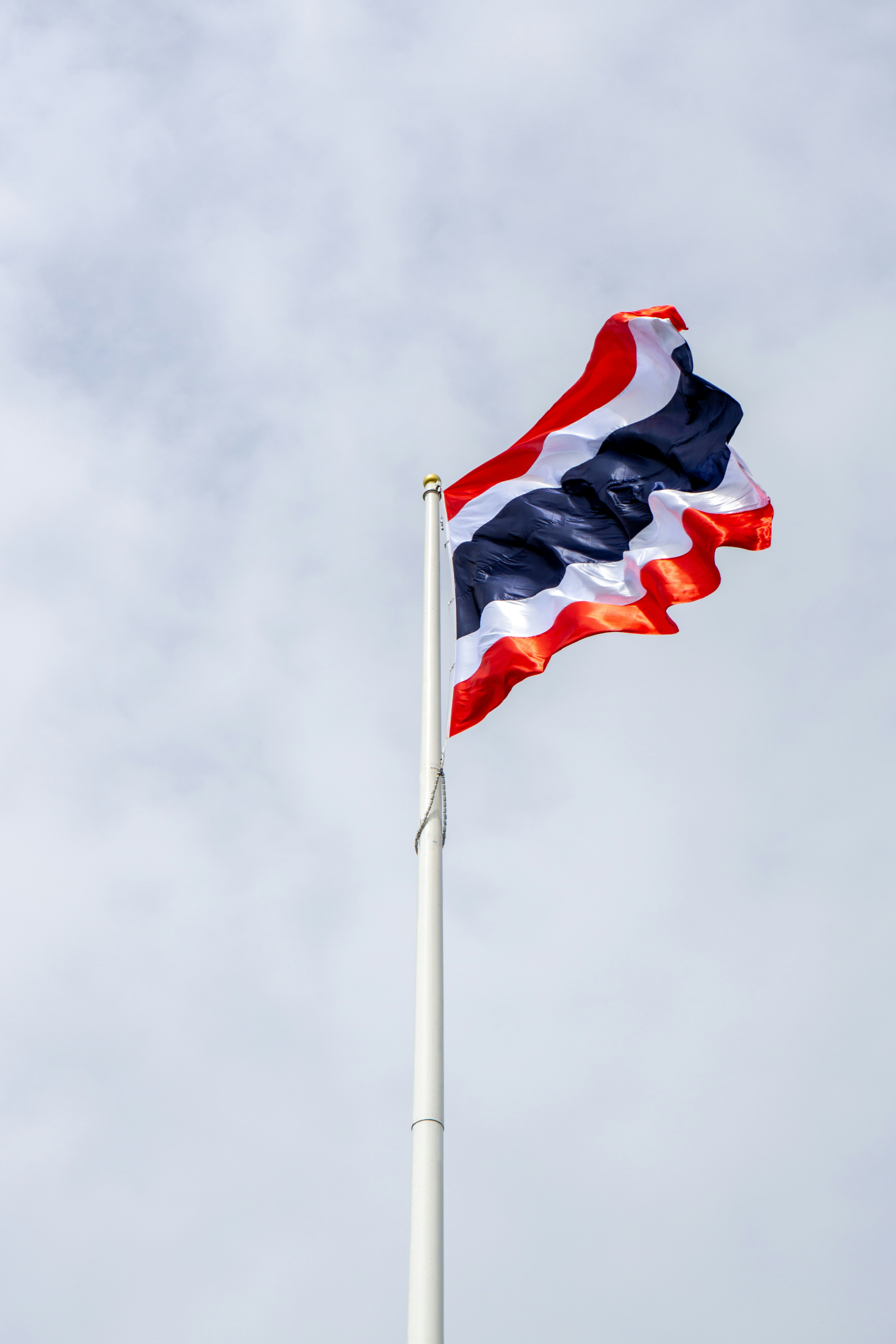 Thai flag waving on a flagpole against the sky