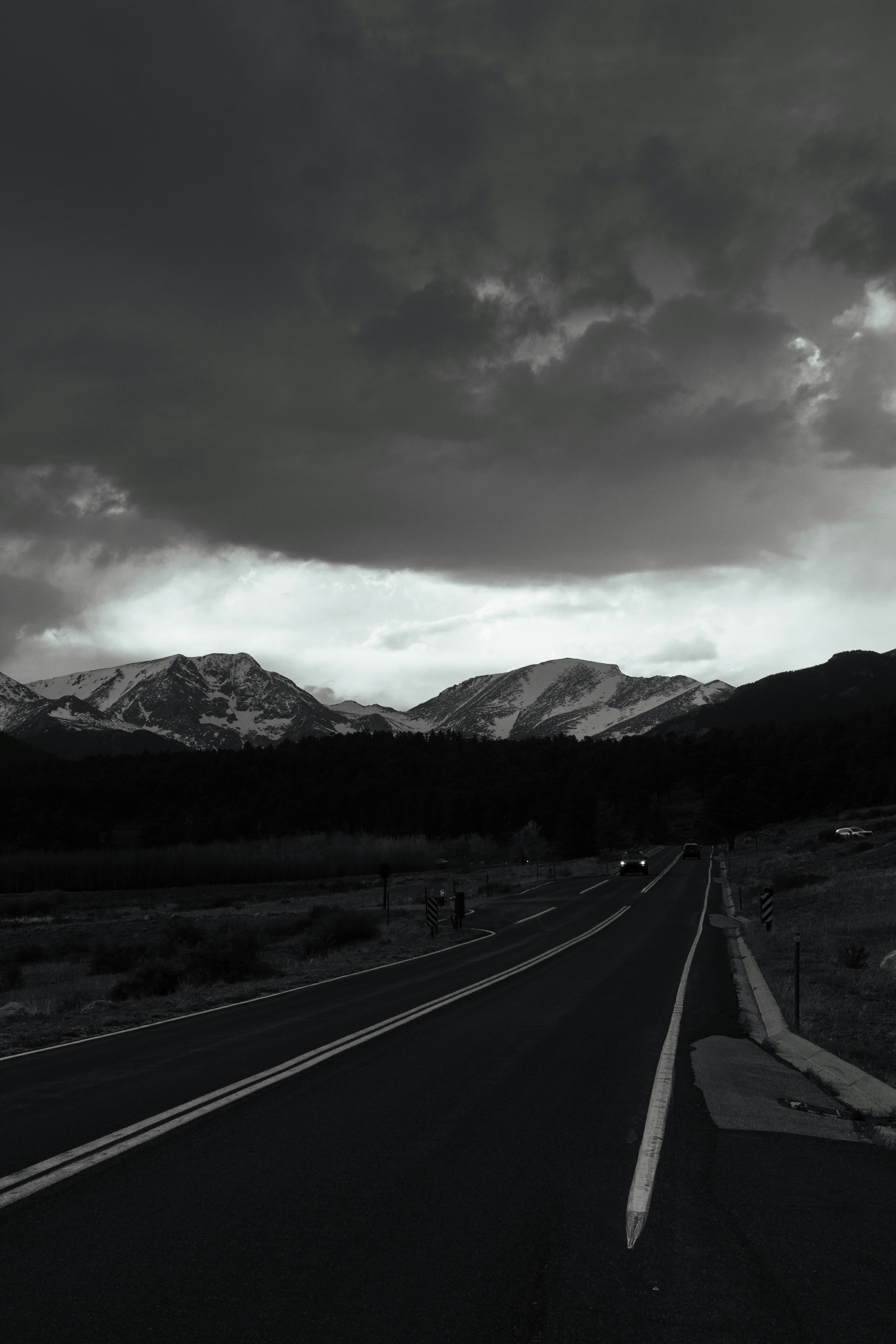 Road leading to snow-capped mountains under stormy sky