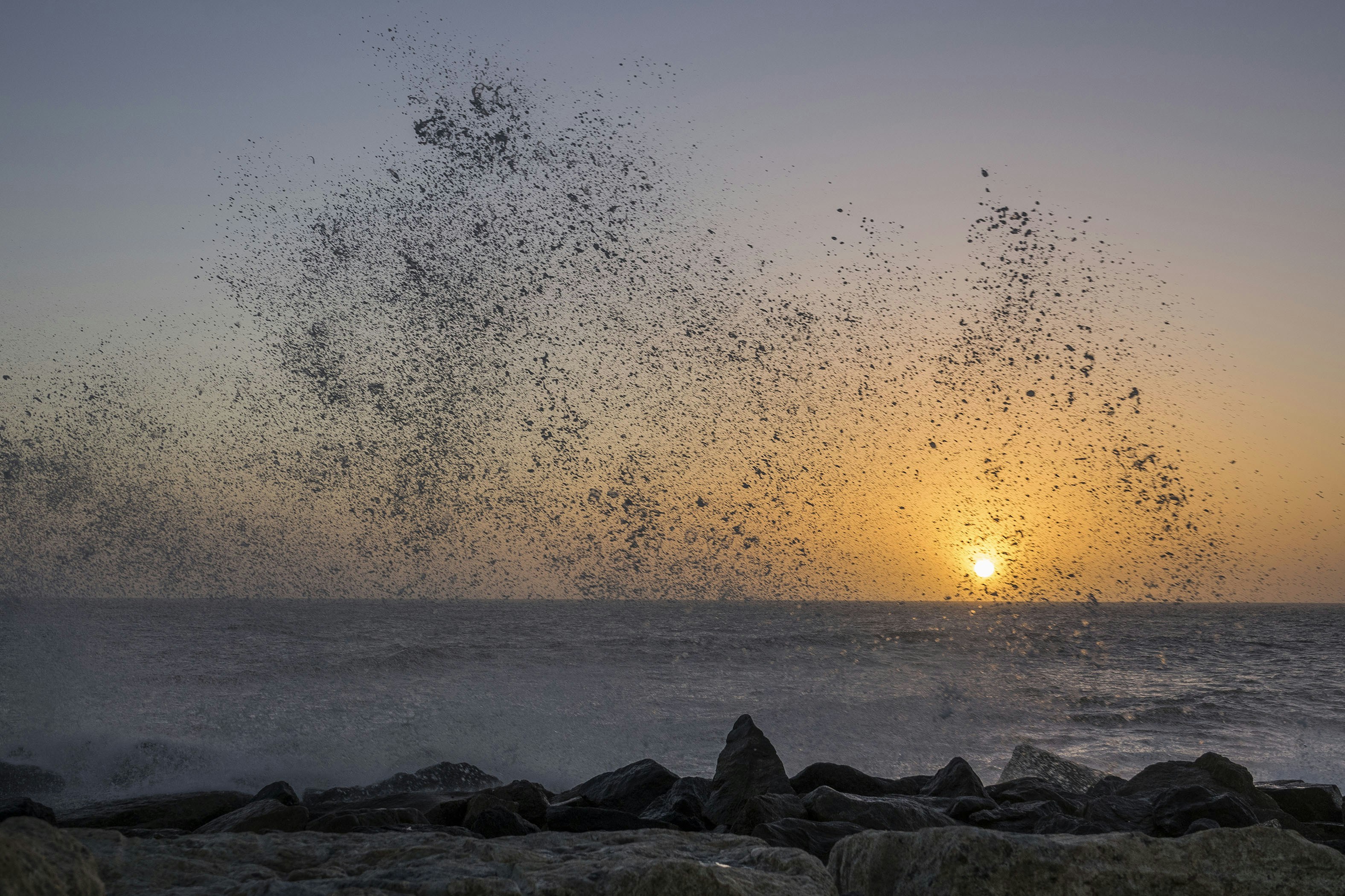 Waves crashing on rocks at sunset.
