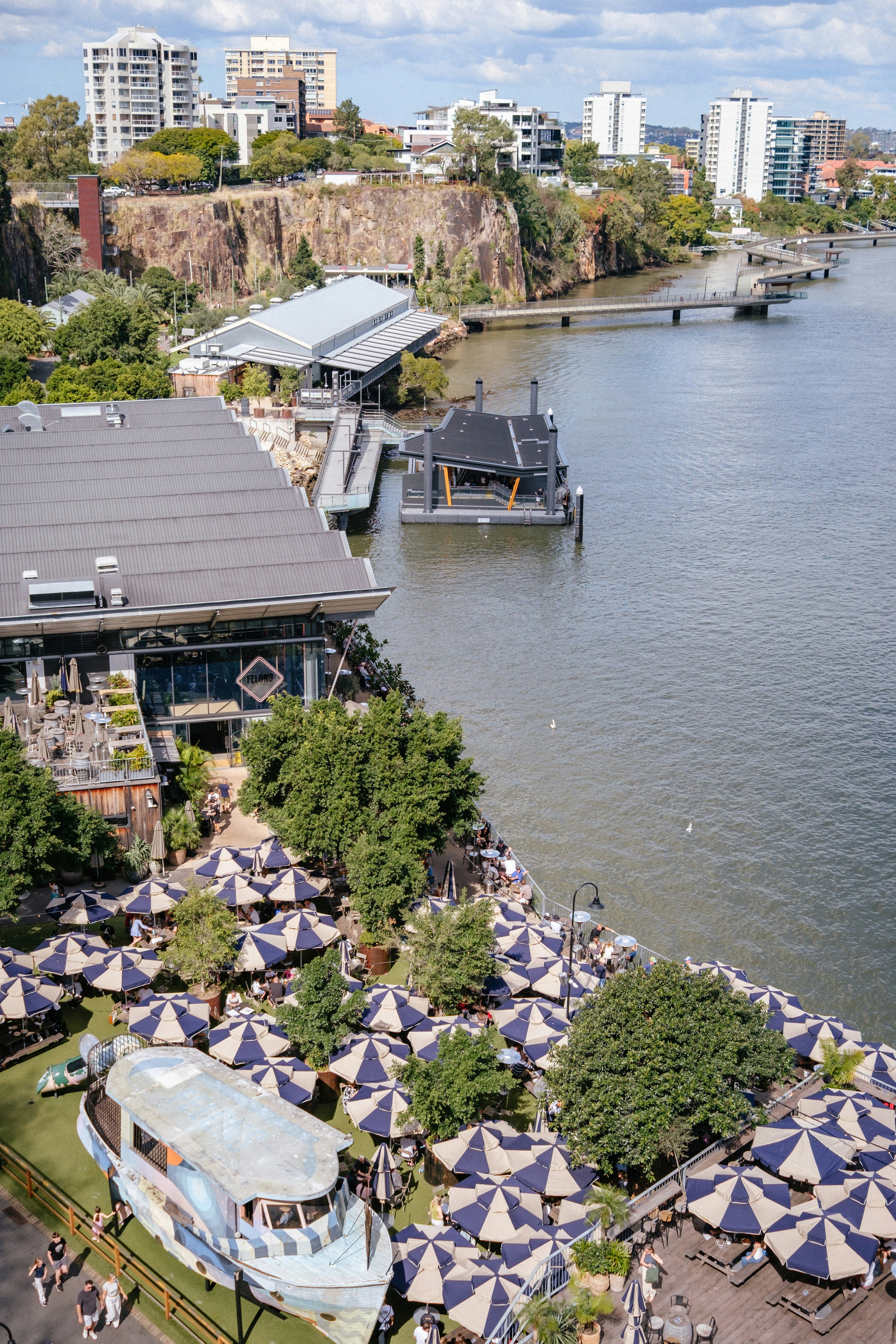 Waterfront dining area with many umbrellas and a boat.