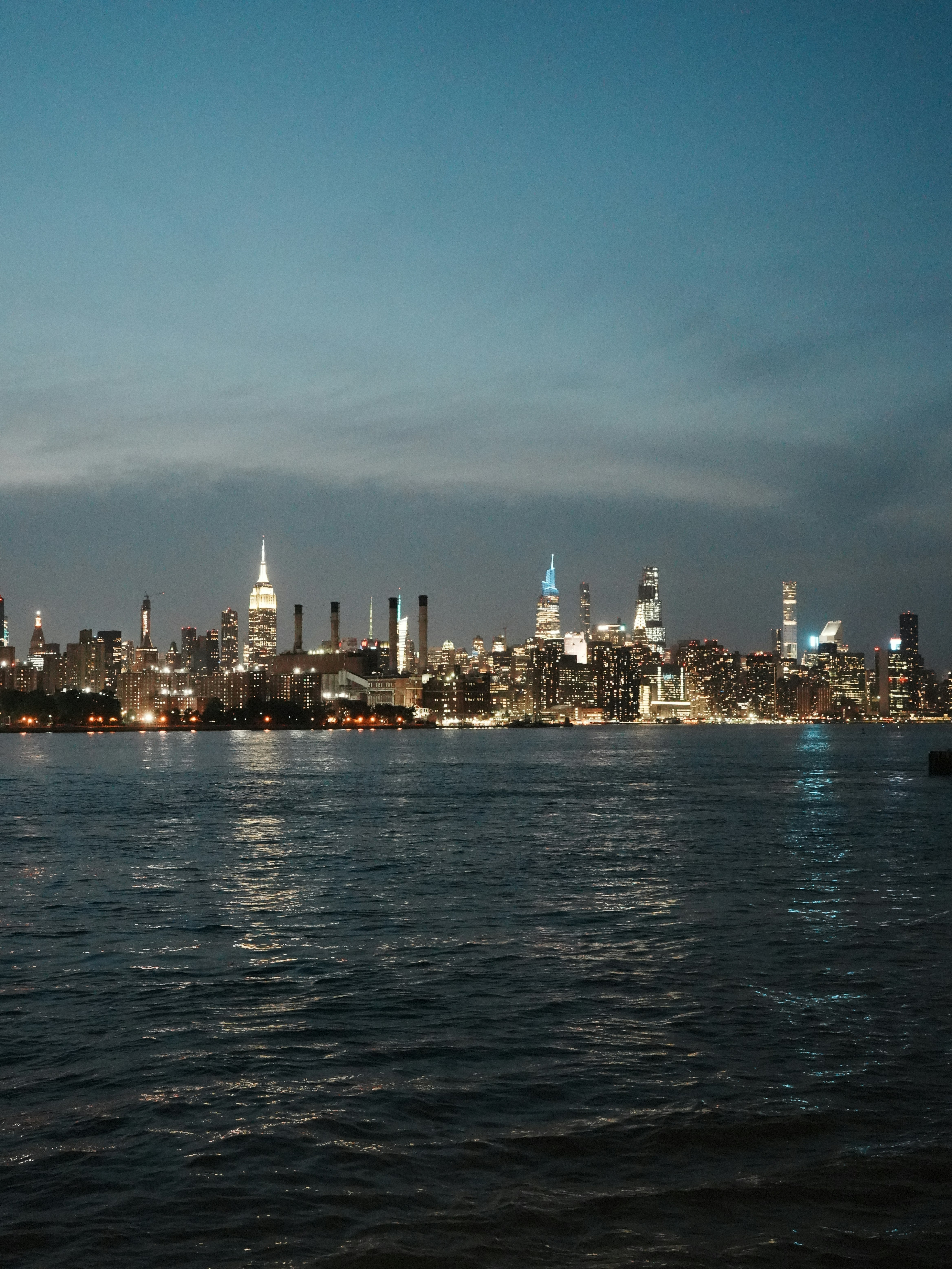 New york city skyline illuminated at dusk across the water.