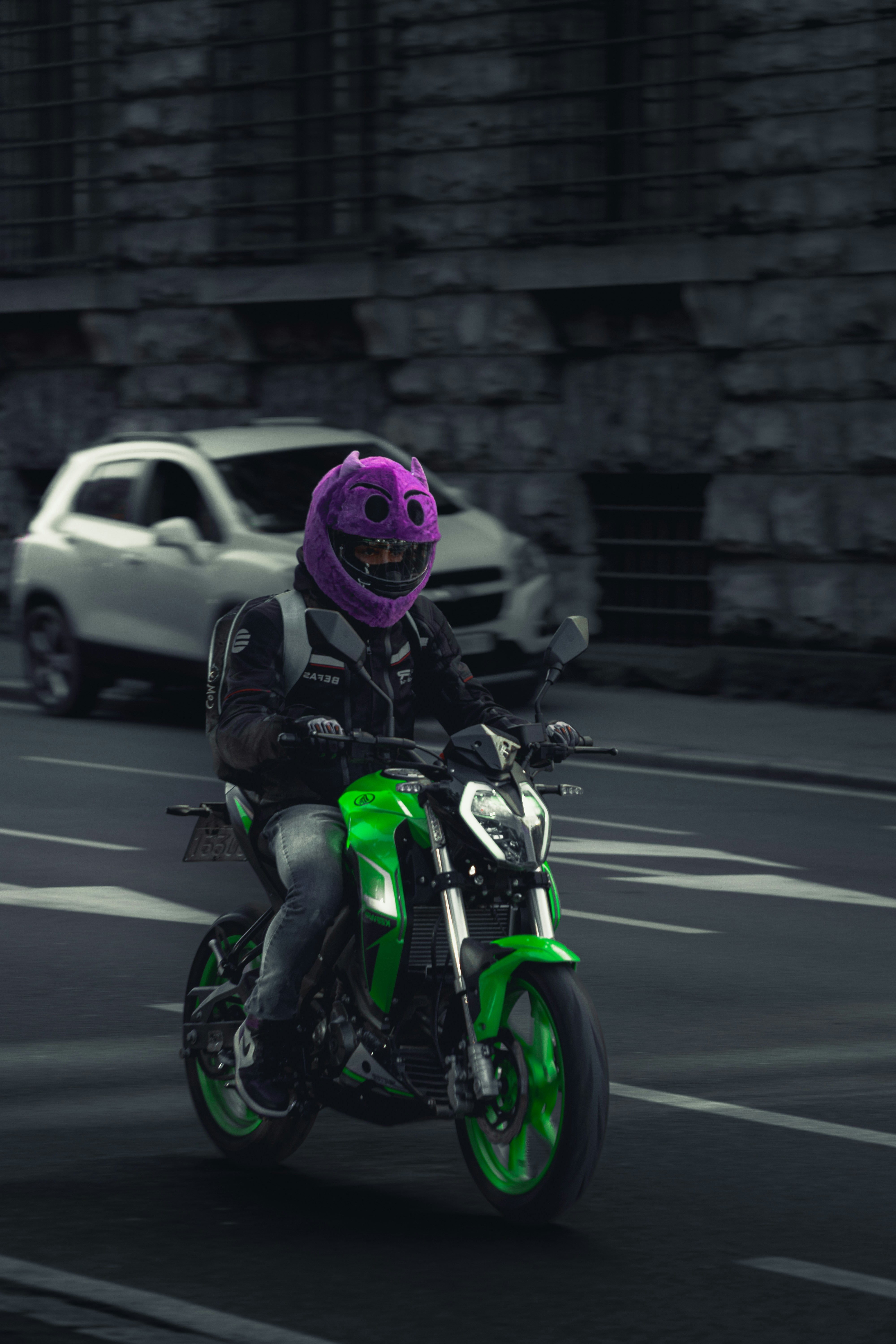 Rider in purple helmet on green motorcycle on street