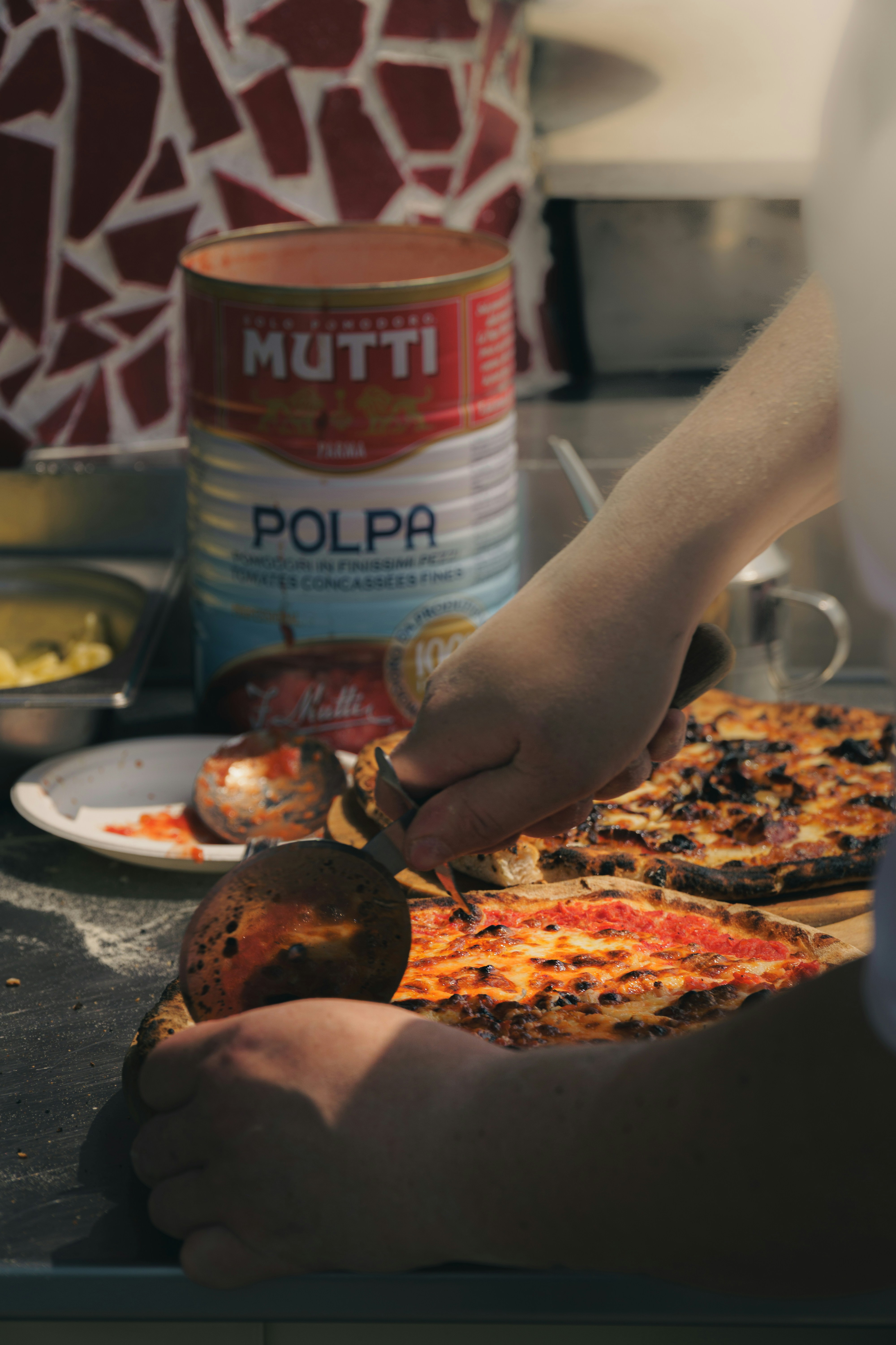 Chef cutting a pizza with a pizza cutter.