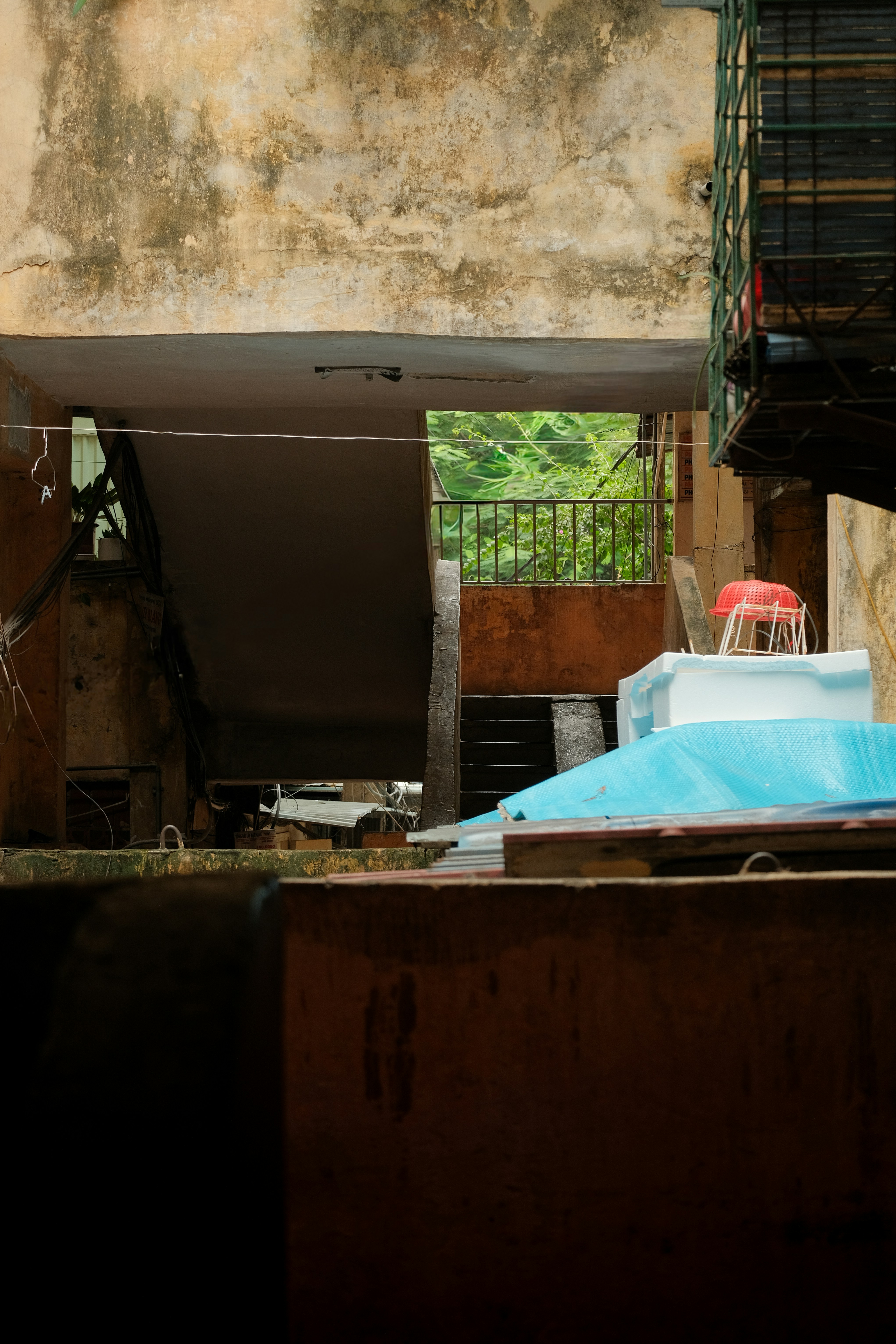 A narrow alleyway between old buildings with greenery visible.